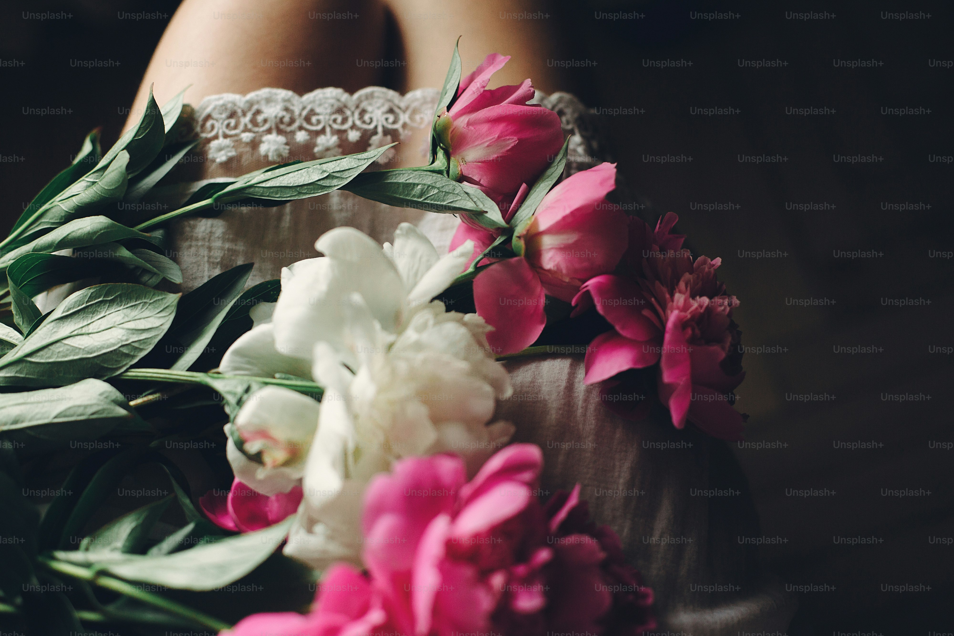 Beautiful pink peonies on legs of boho girl in white bohemian dress ...