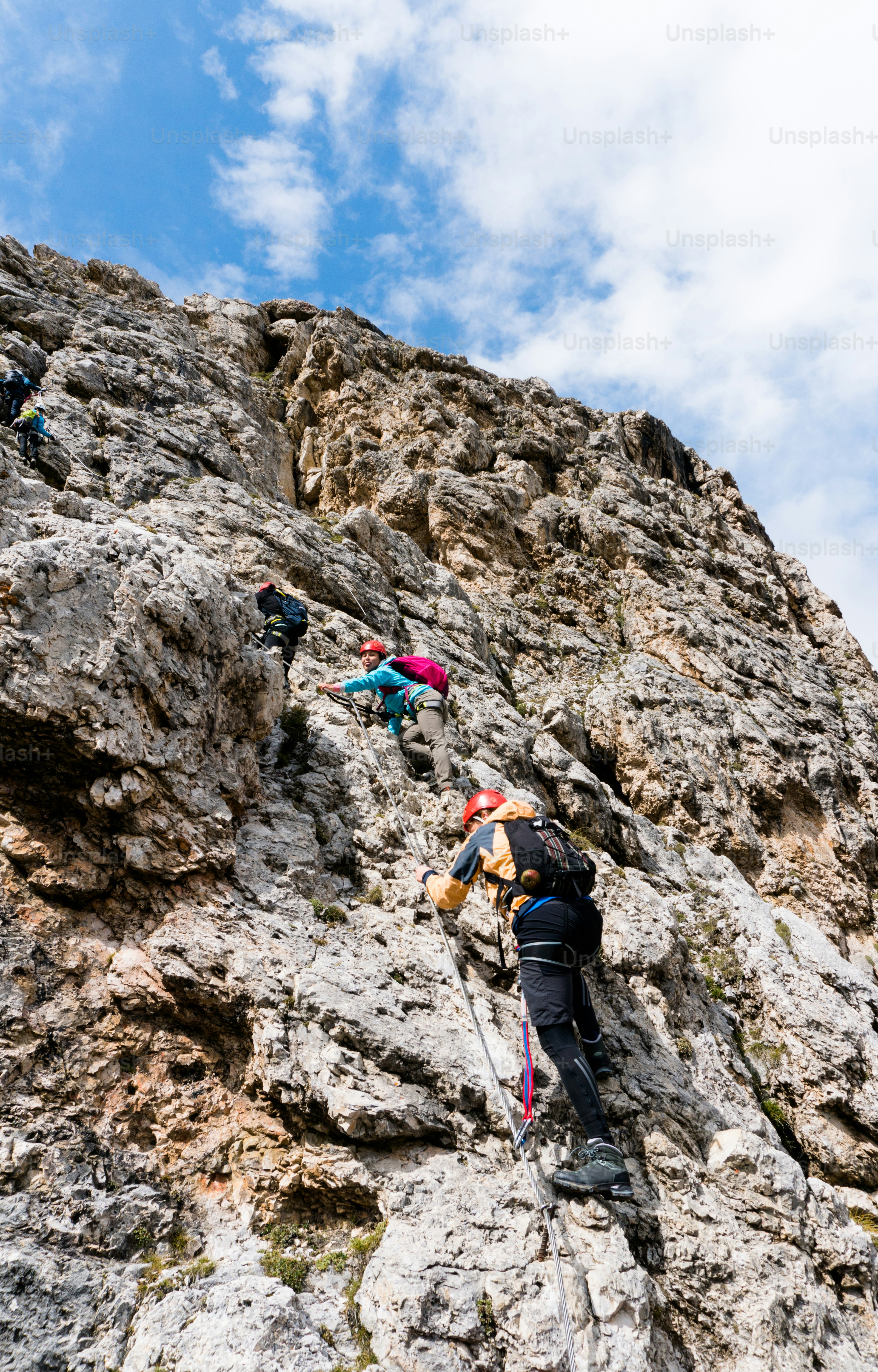 Three mountain climbers on a difficult Via Ferrata in the Dolomites in ...