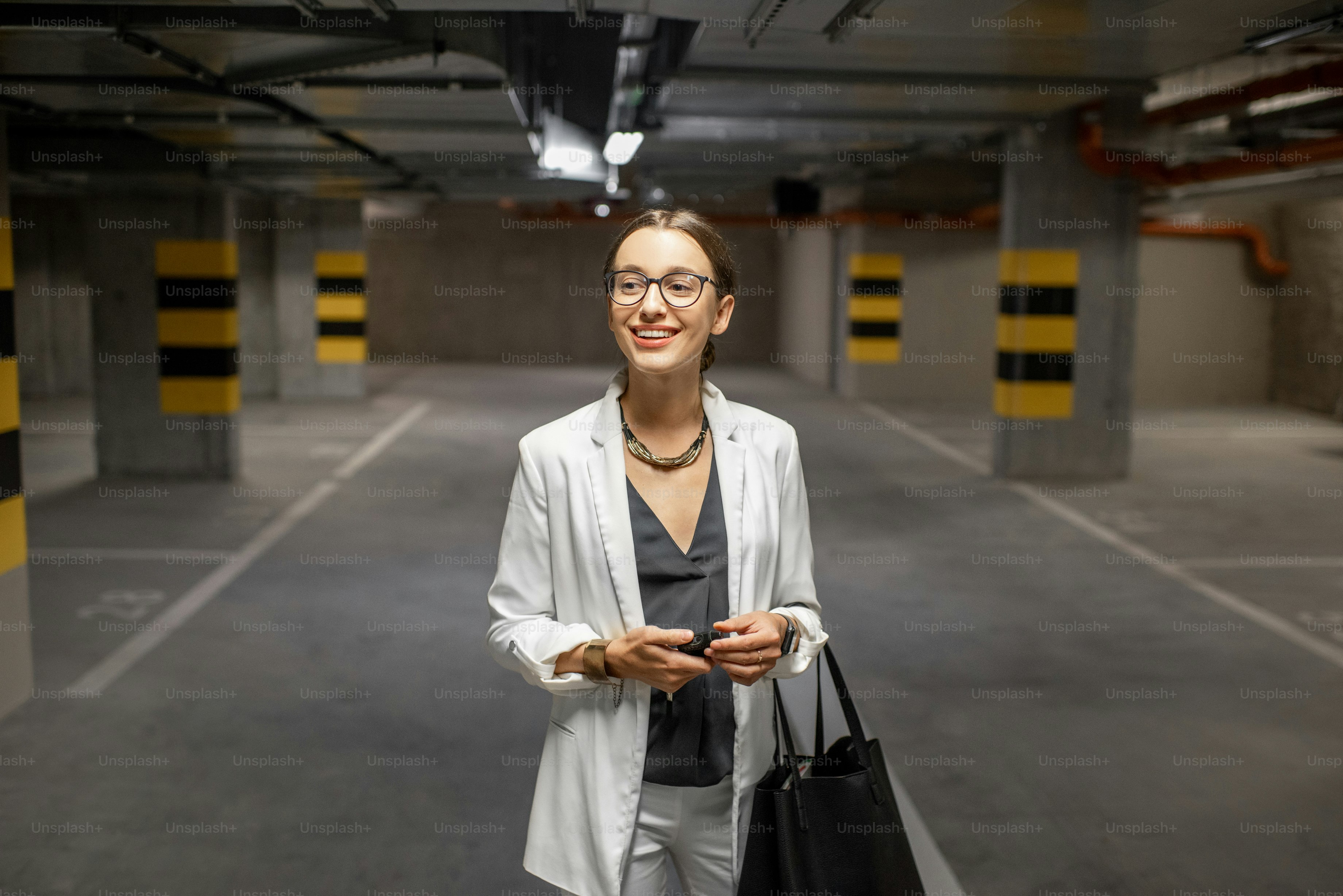 Young business woman walking with car keys in the underground parking ...