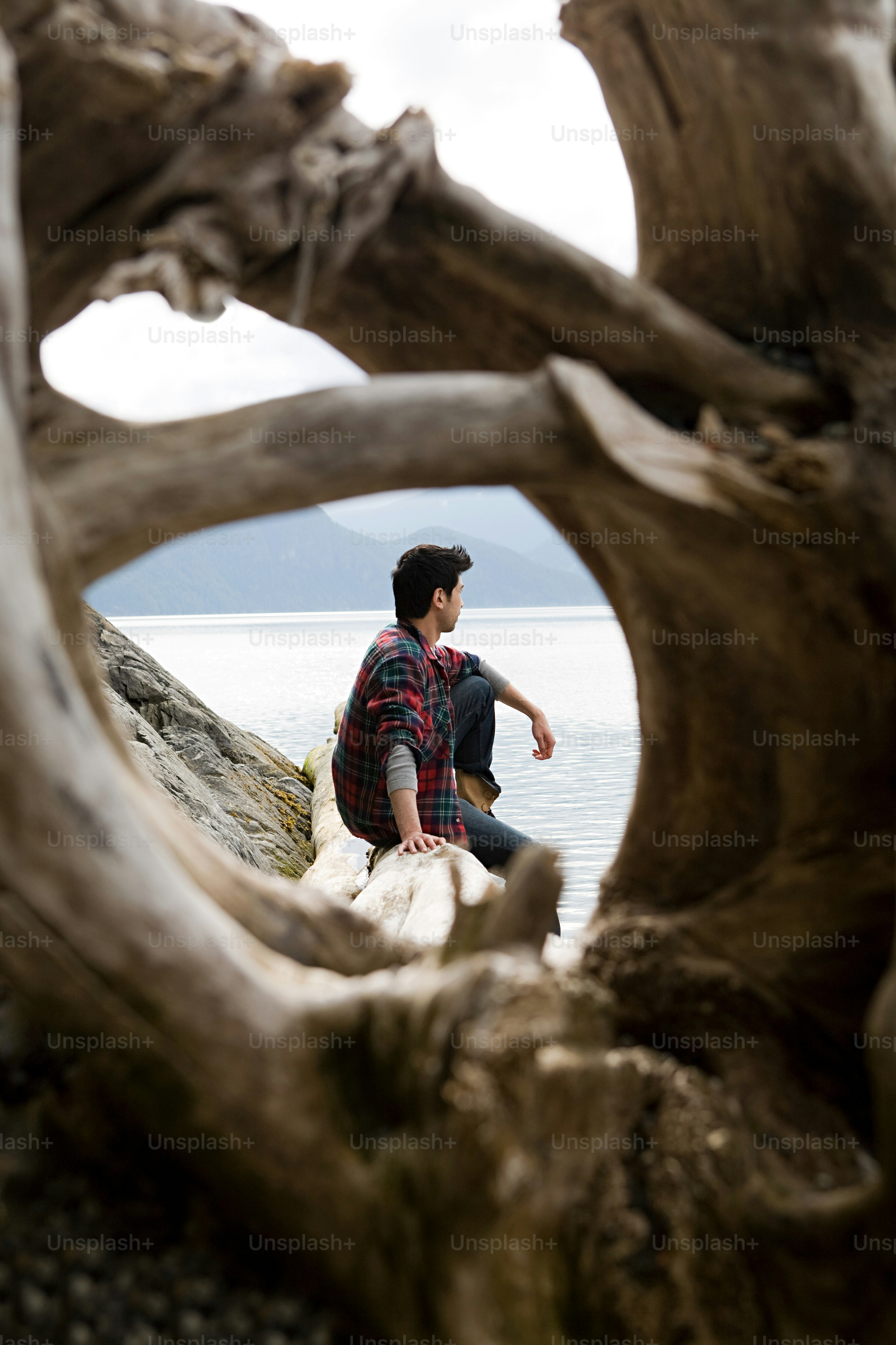Un homme assis sur un rocher à côté d’un plan d’eau photo – Adulte ...