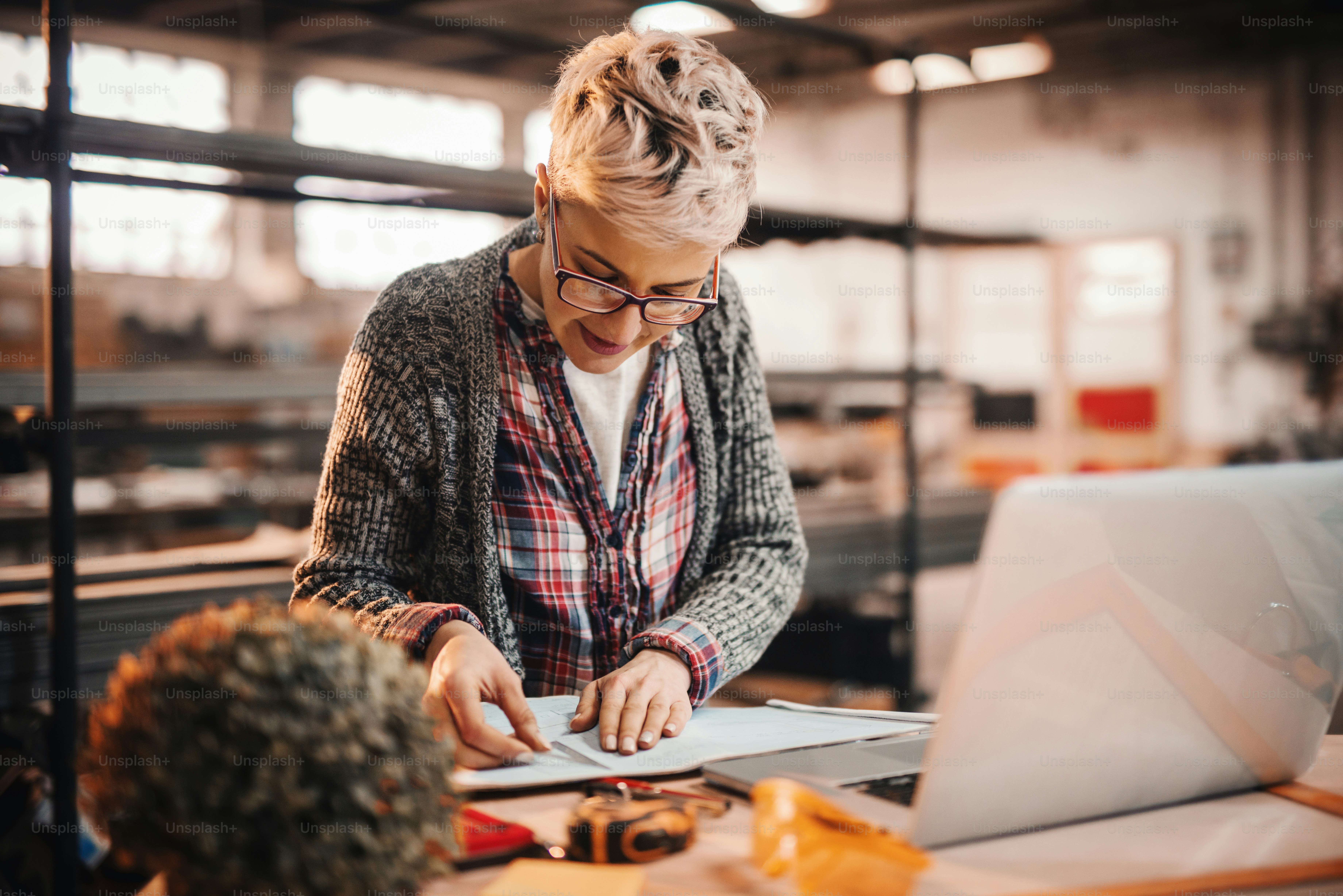 Woman doing paperwork while standing in carpenter workshop. Female ...