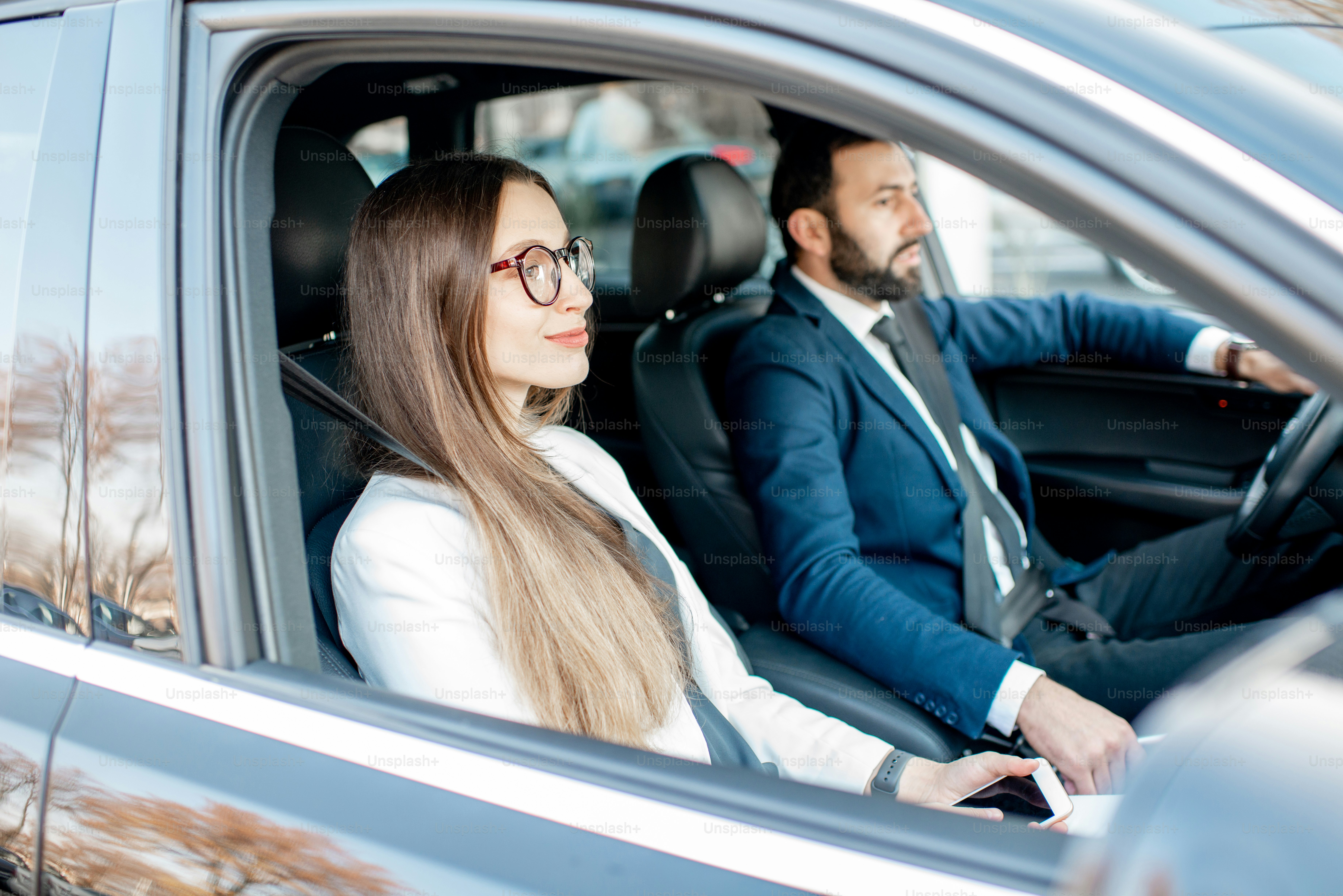Businessman and woman dressed in the suits driving luxury car, view ...