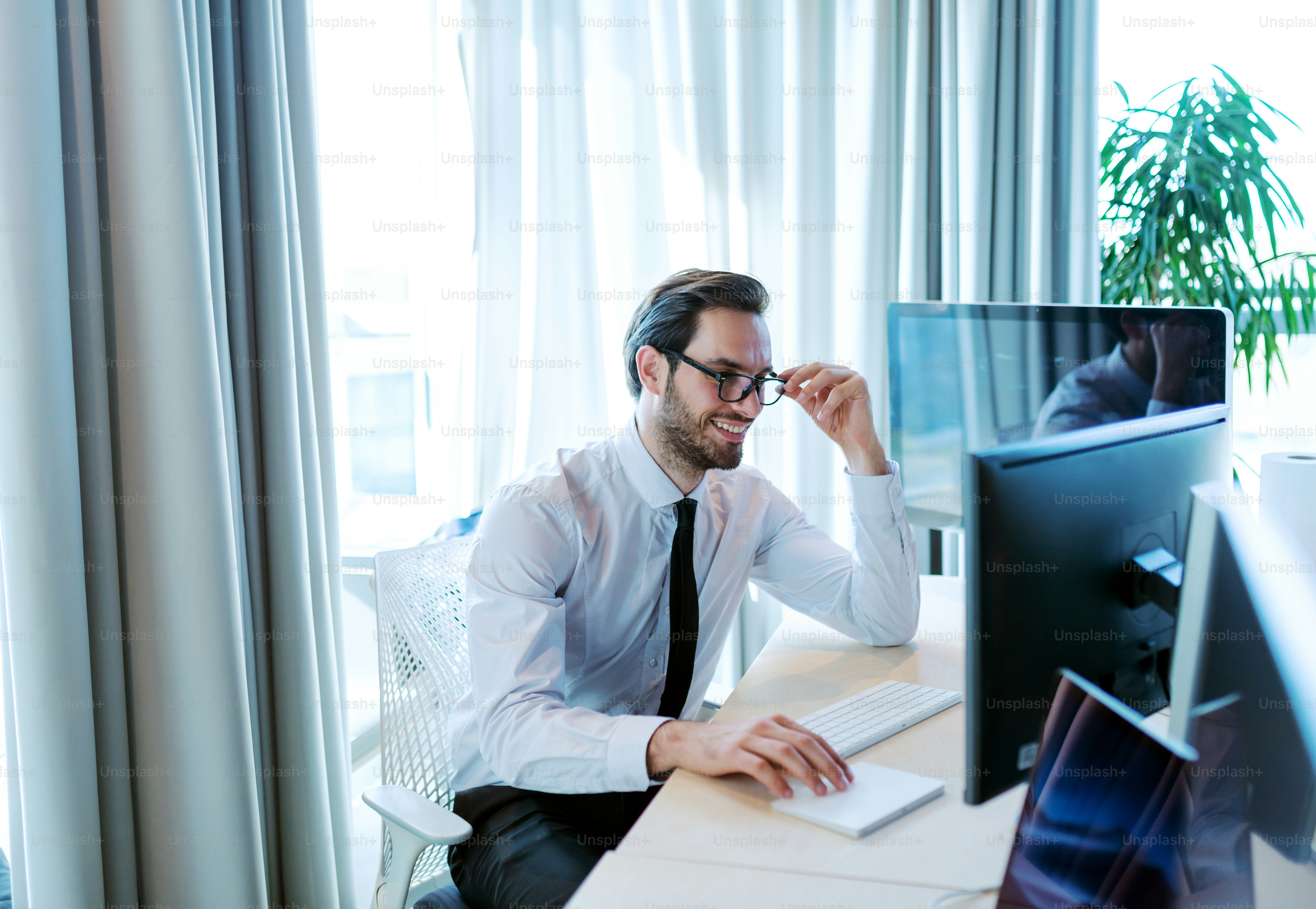 Smiling corporate worker in formal wear using desktop computer and ...