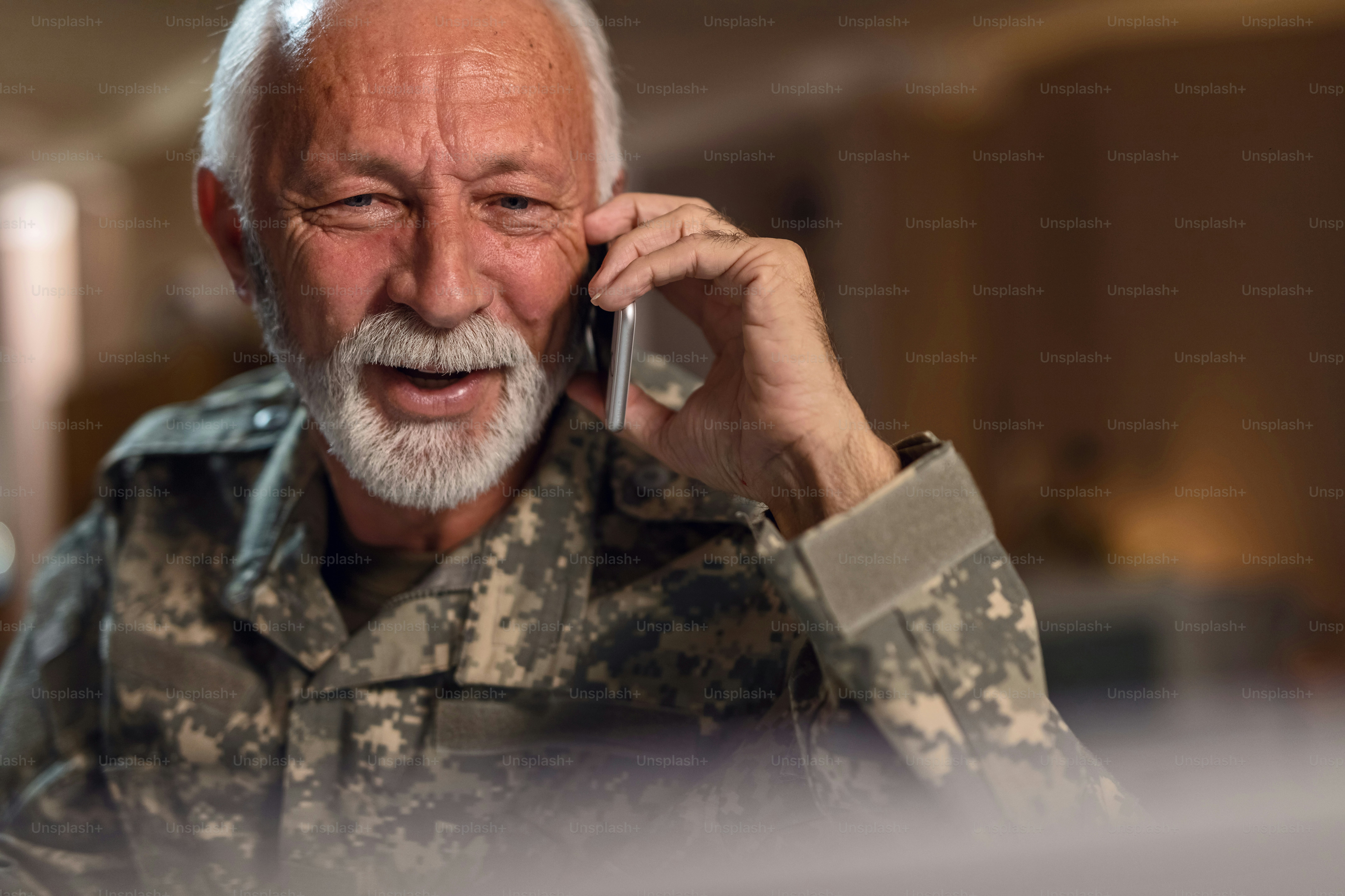Smiling senior soldier using mobile phone and talking to someone in the ...