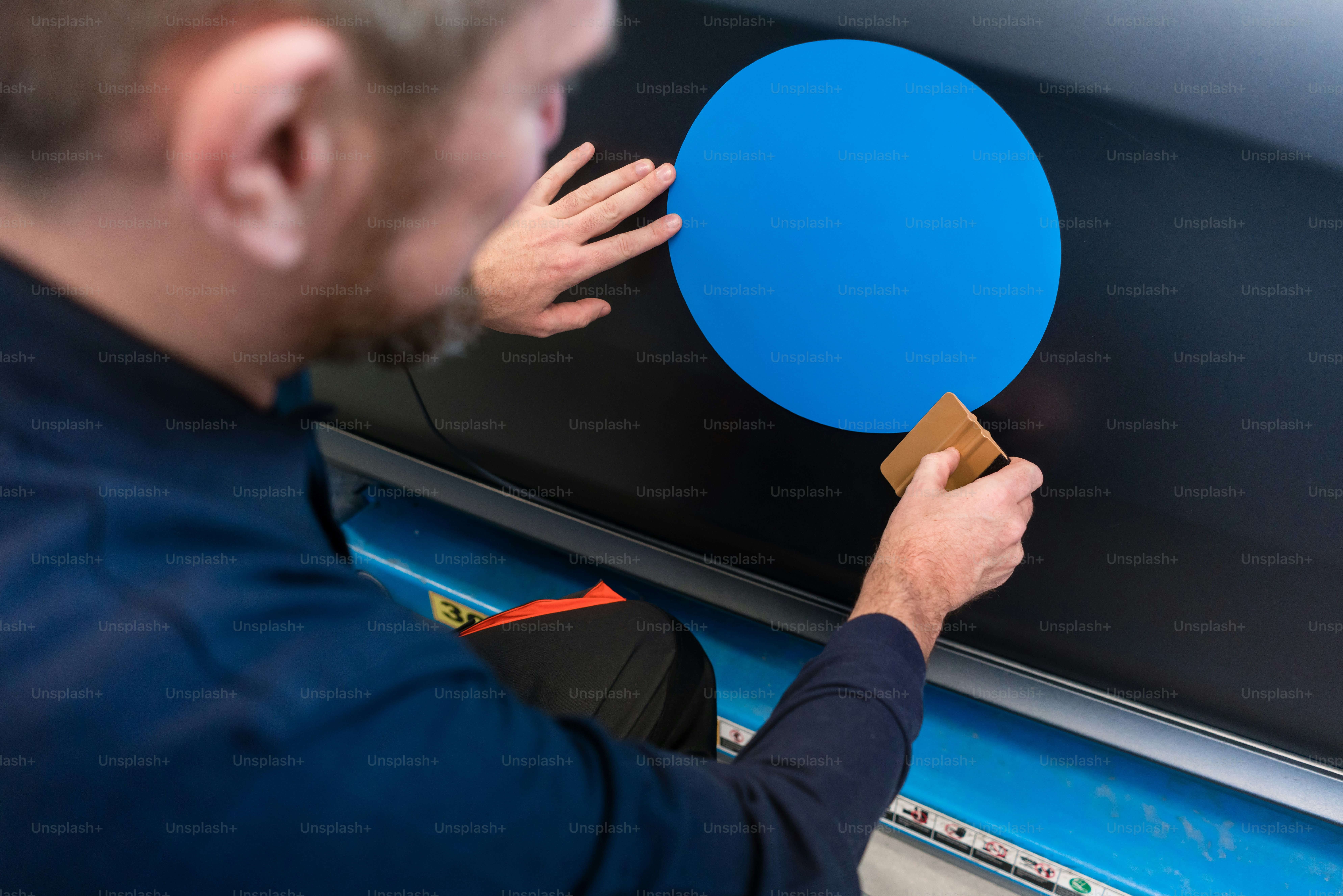 Man putting promotional sticker with company slogan on a car photo ...