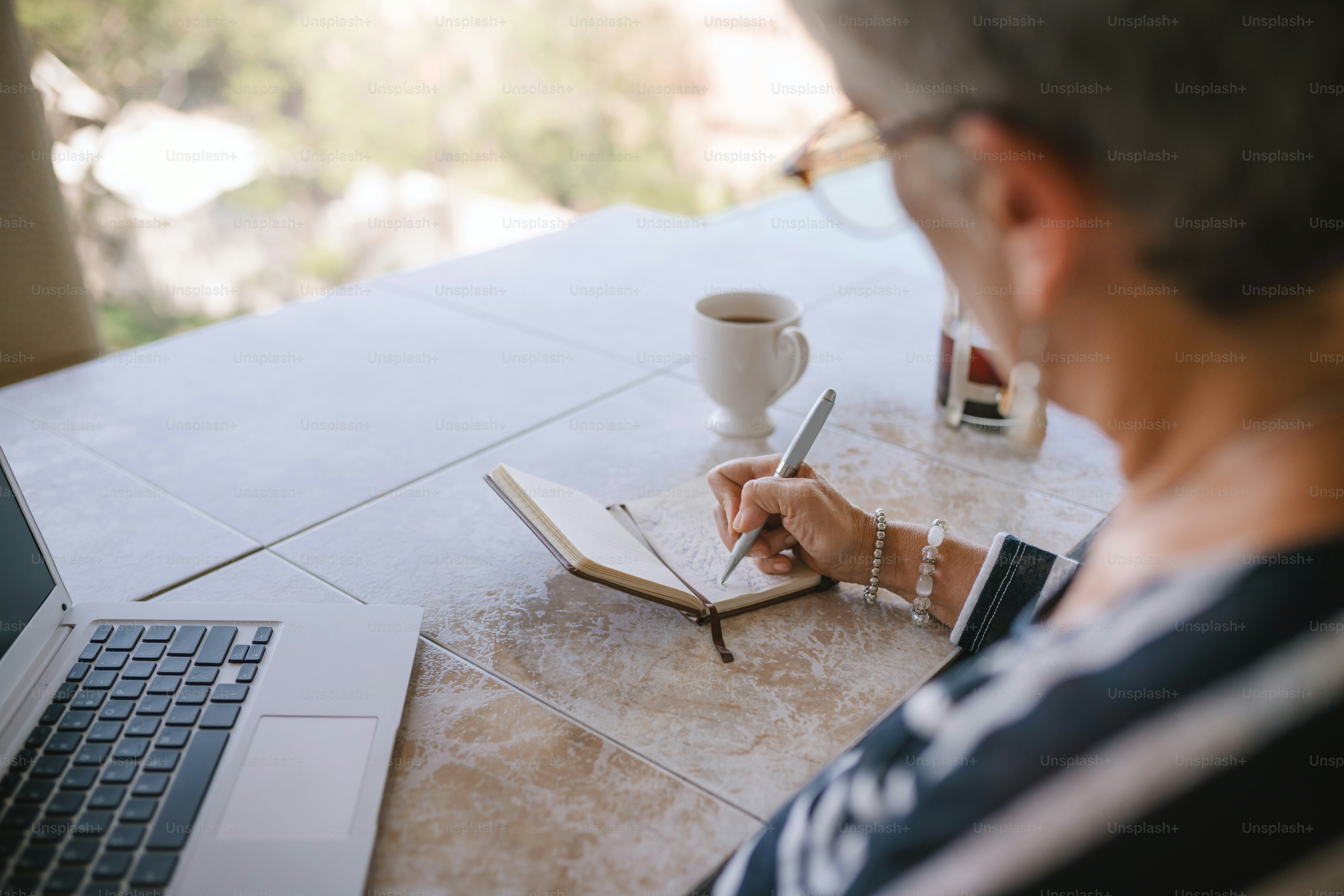 Foto Primer plano de una mujer mayor escribiendo en un cuaderno en casa ...
