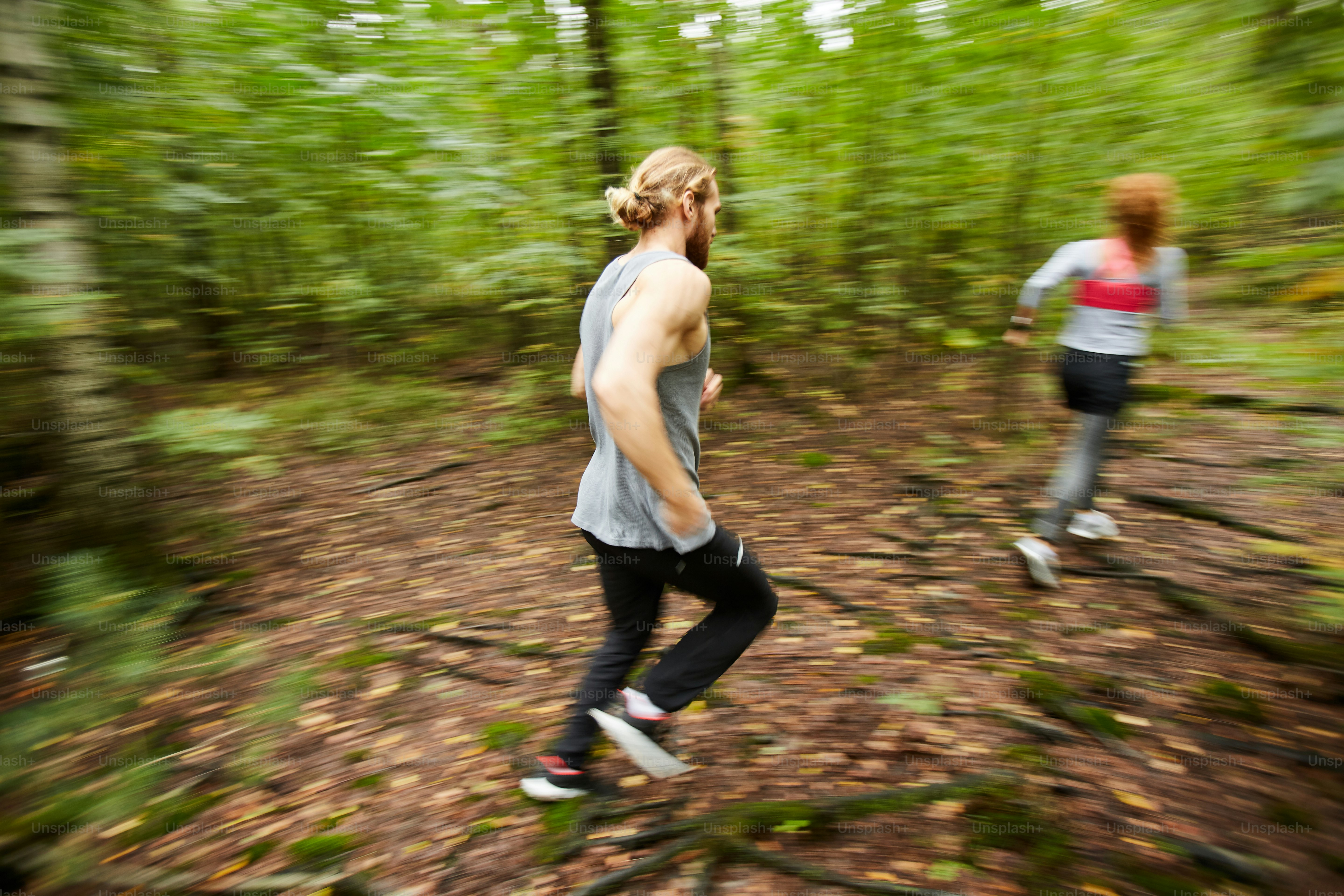 Active young man running after his girlfriend while moving down forest ...