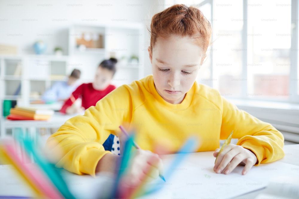 Foto Niña que se concentra en el dibujo individual en la lección sobre ... Foto Niña que se concentra en el dibujo individual en la lección sobre ...