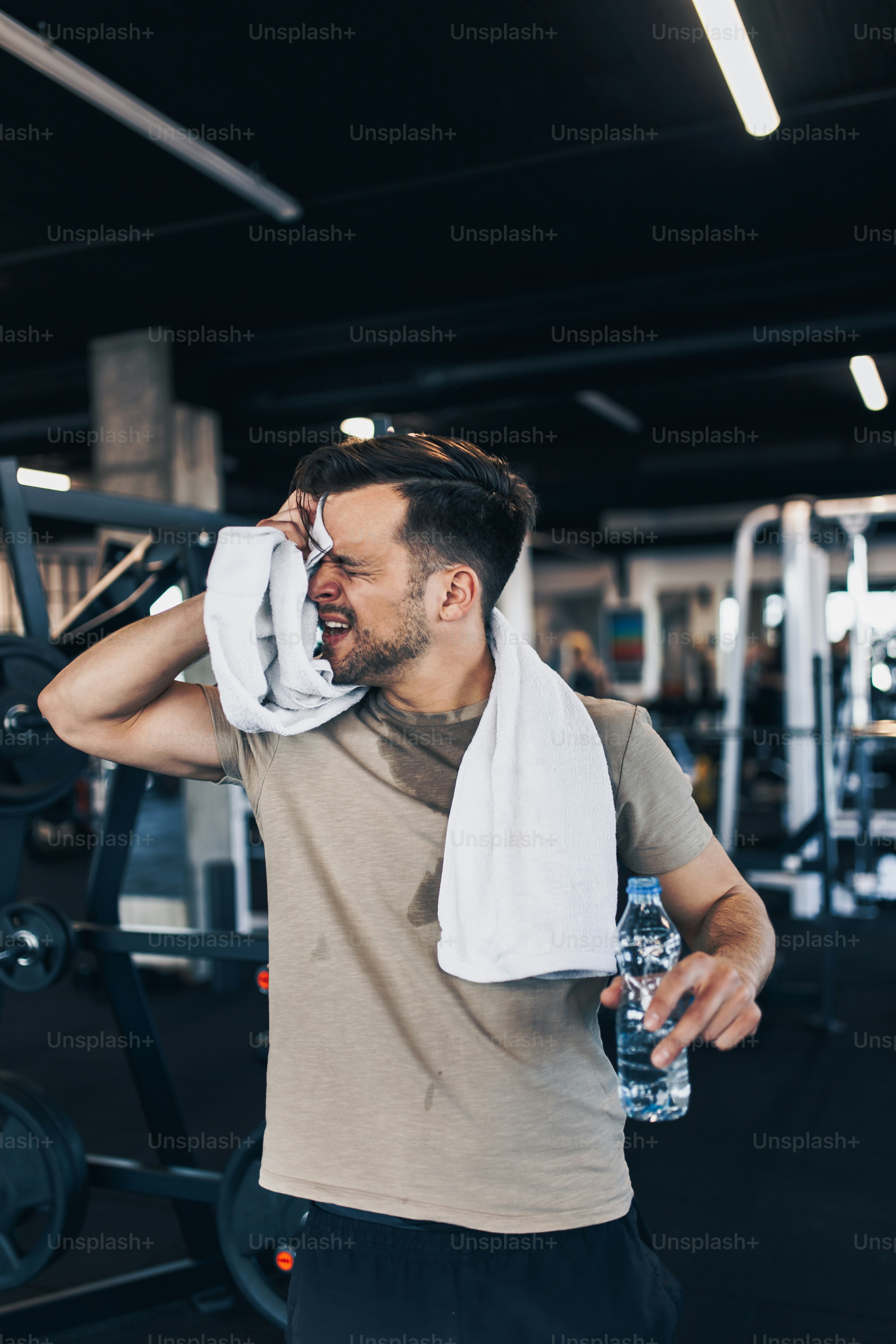 Young exhausted man relaxing in fitness gym after successful workout ...