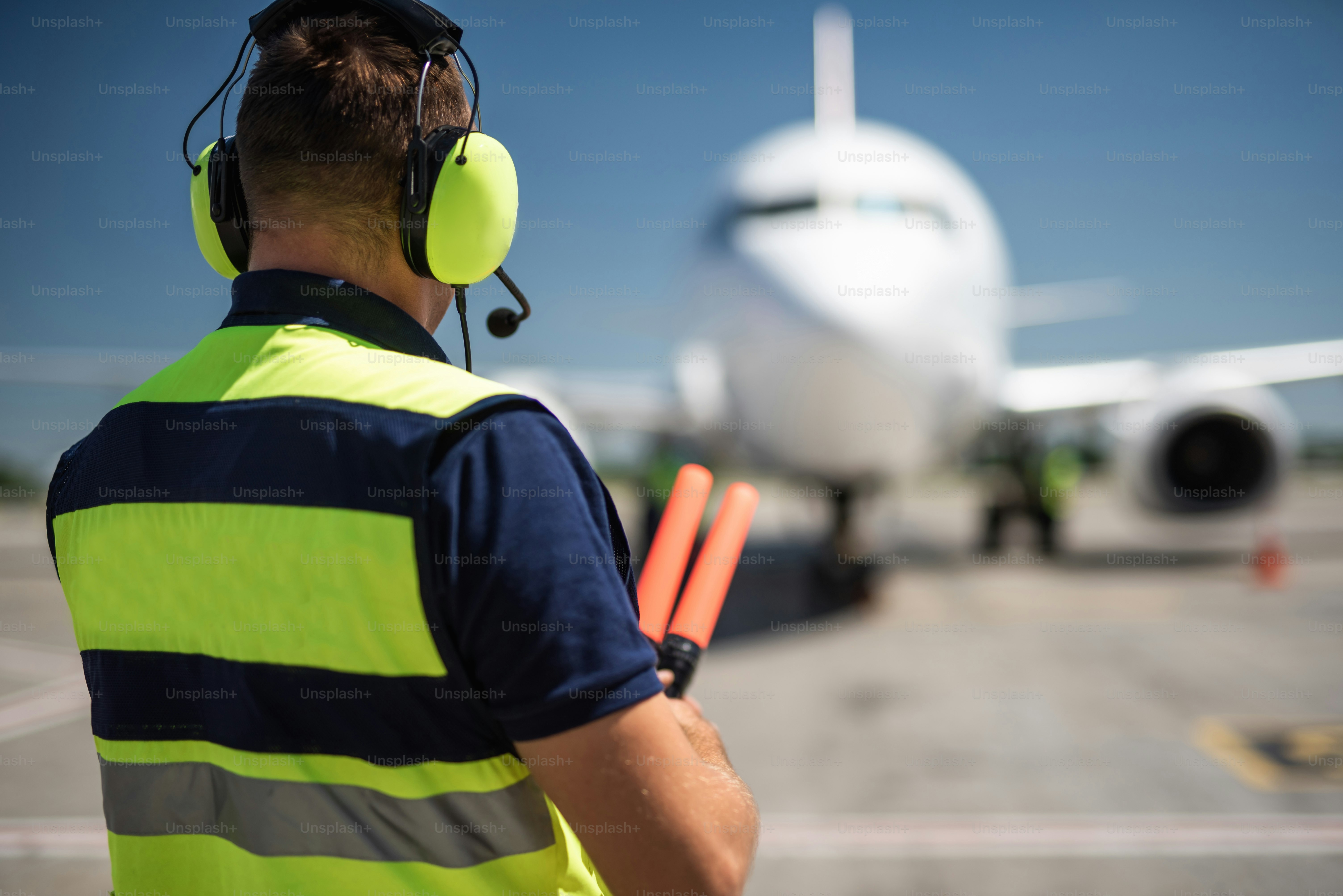 Directing the jet. Back view of aviation marshaller at airport ...