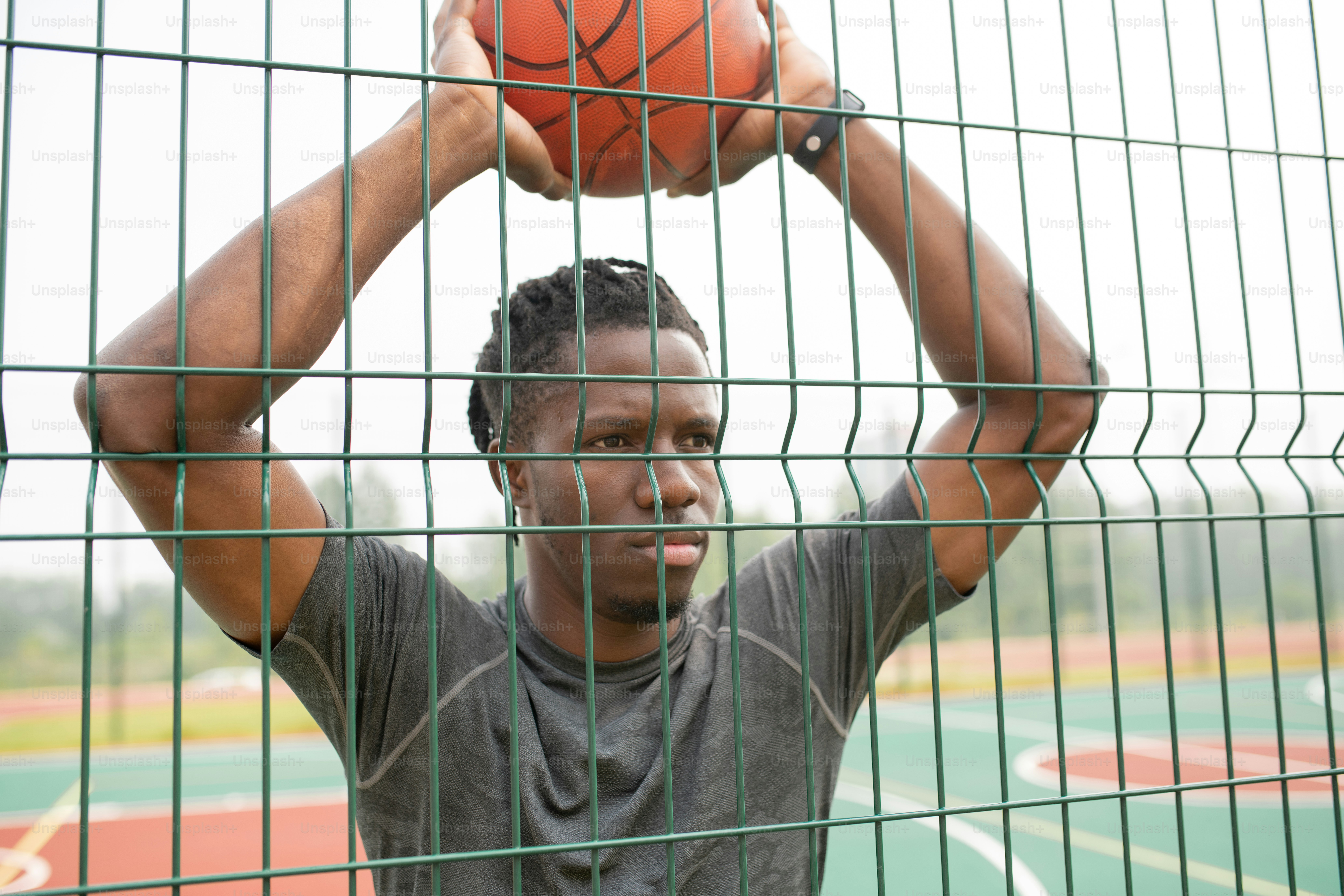 Young basketball player of African ethnicity holding ball over his head ...