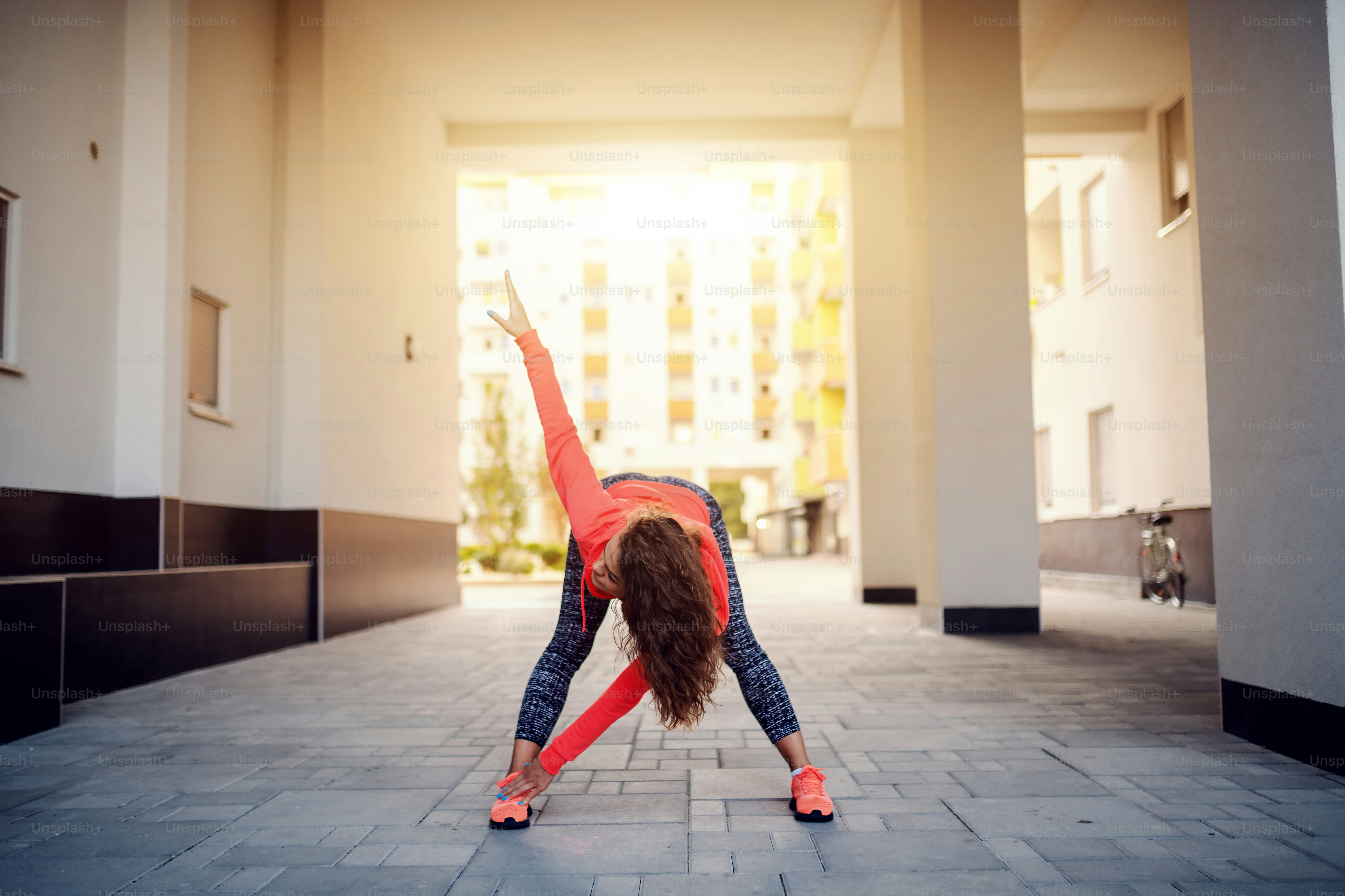 Full length of fit attractive woman in sportswear and with curly hair ...
