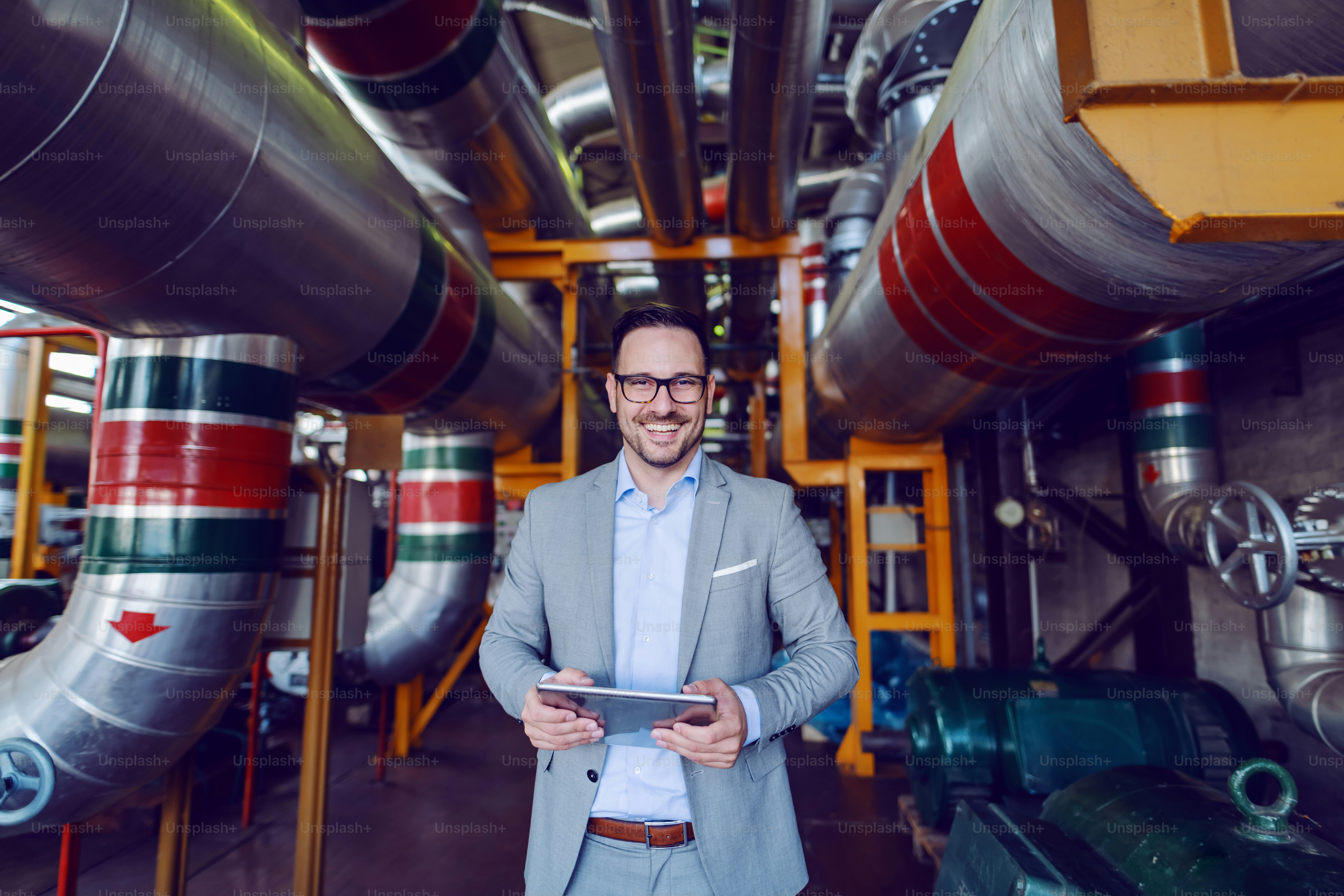 Foto Supervisor guapo y sonriente en traje gris sosteniendo una tableta ...