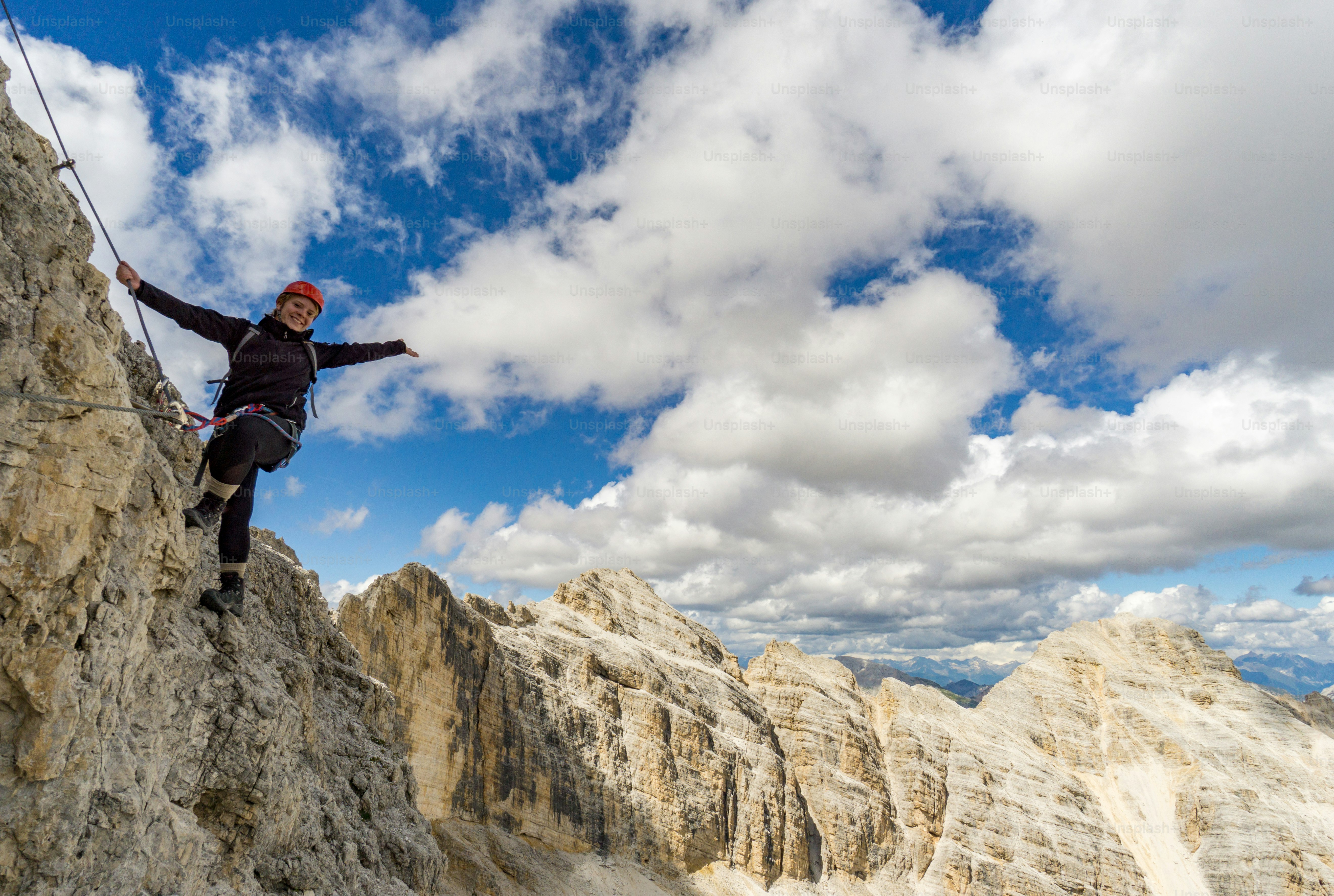 Horizontal view of a female mountain climber on a steep Via Ferrata in ...