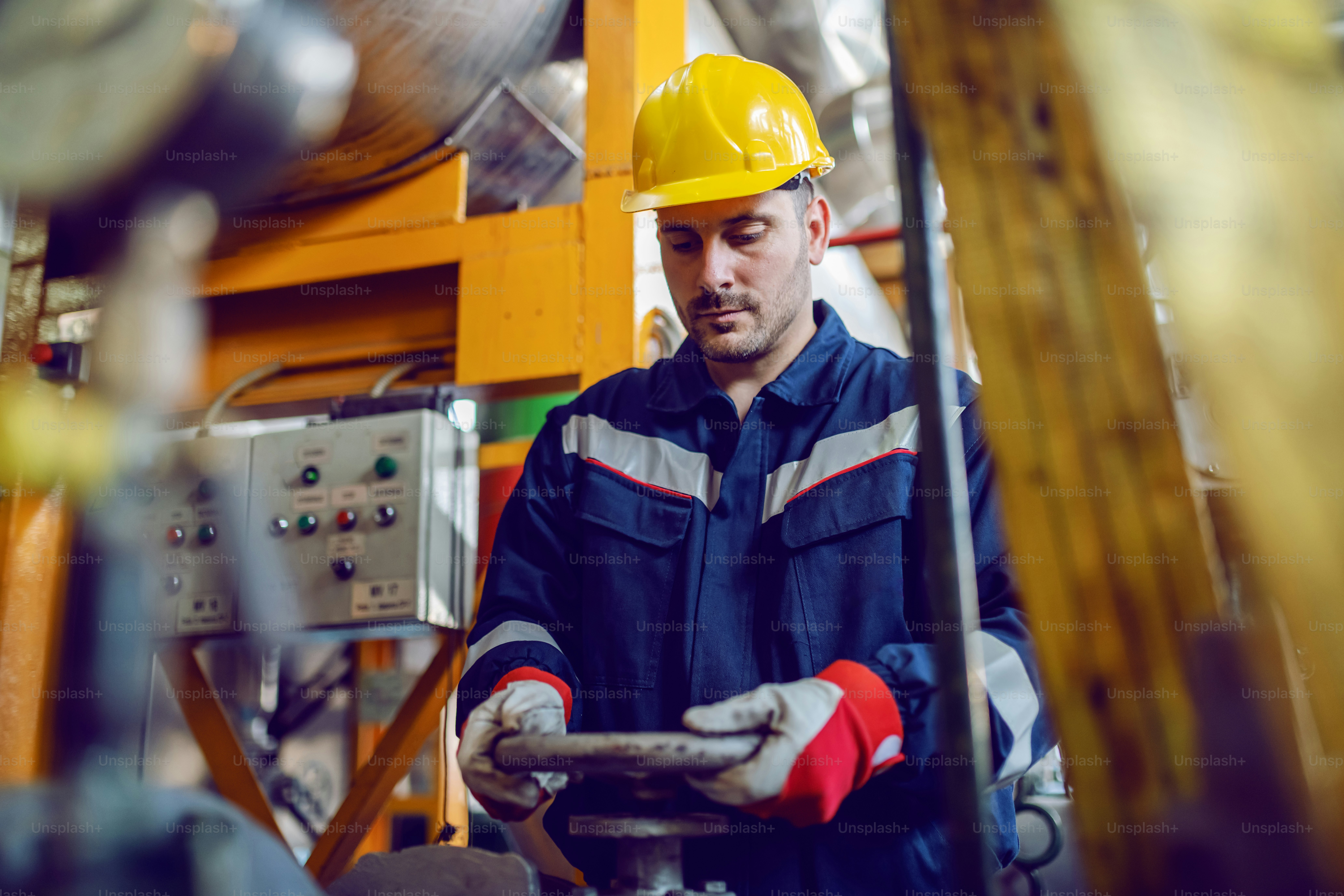Hardworking energy plant worker in working suit and with protective ...