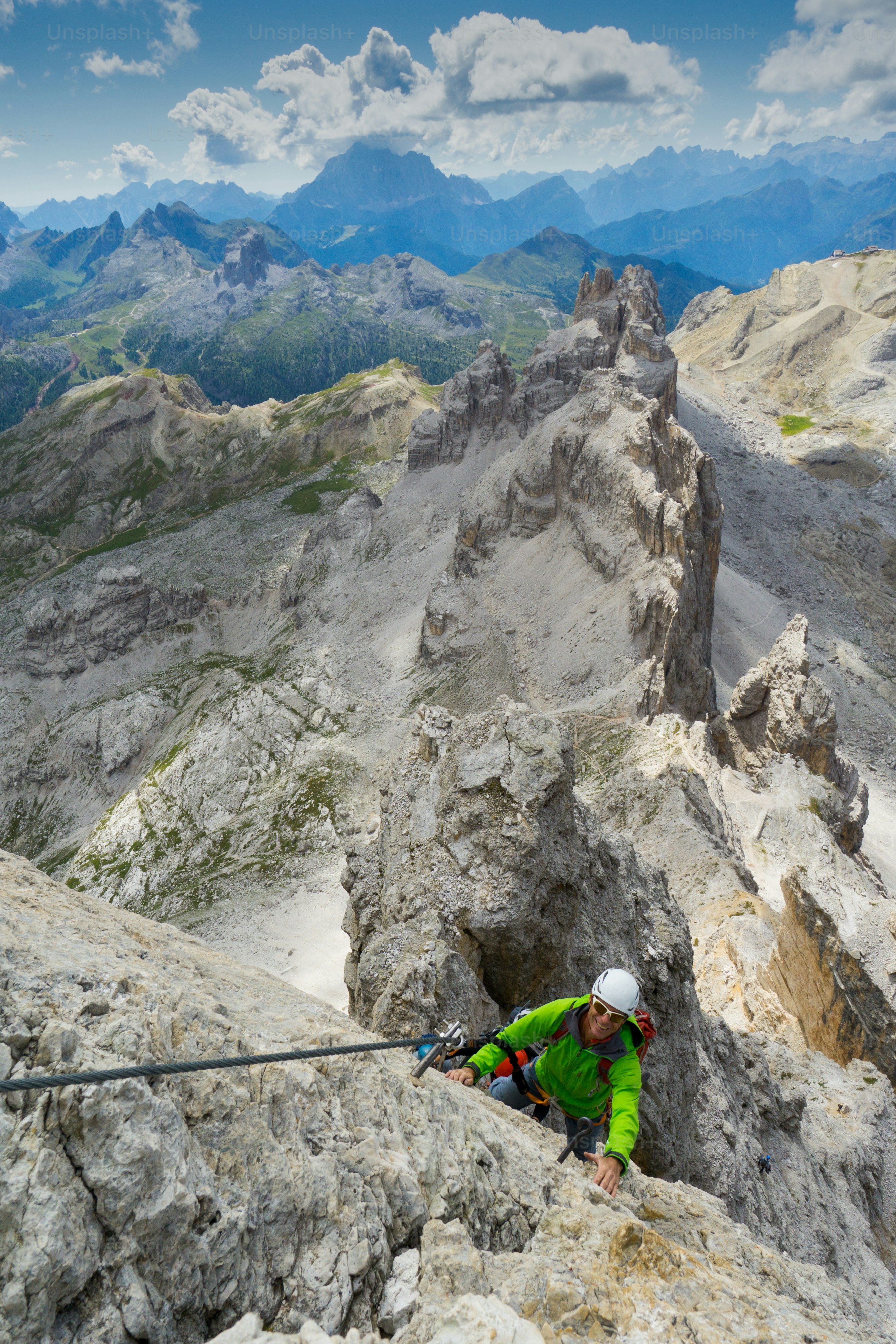 Handsome male climber on a steep and exposed rock face climbs a Via ...