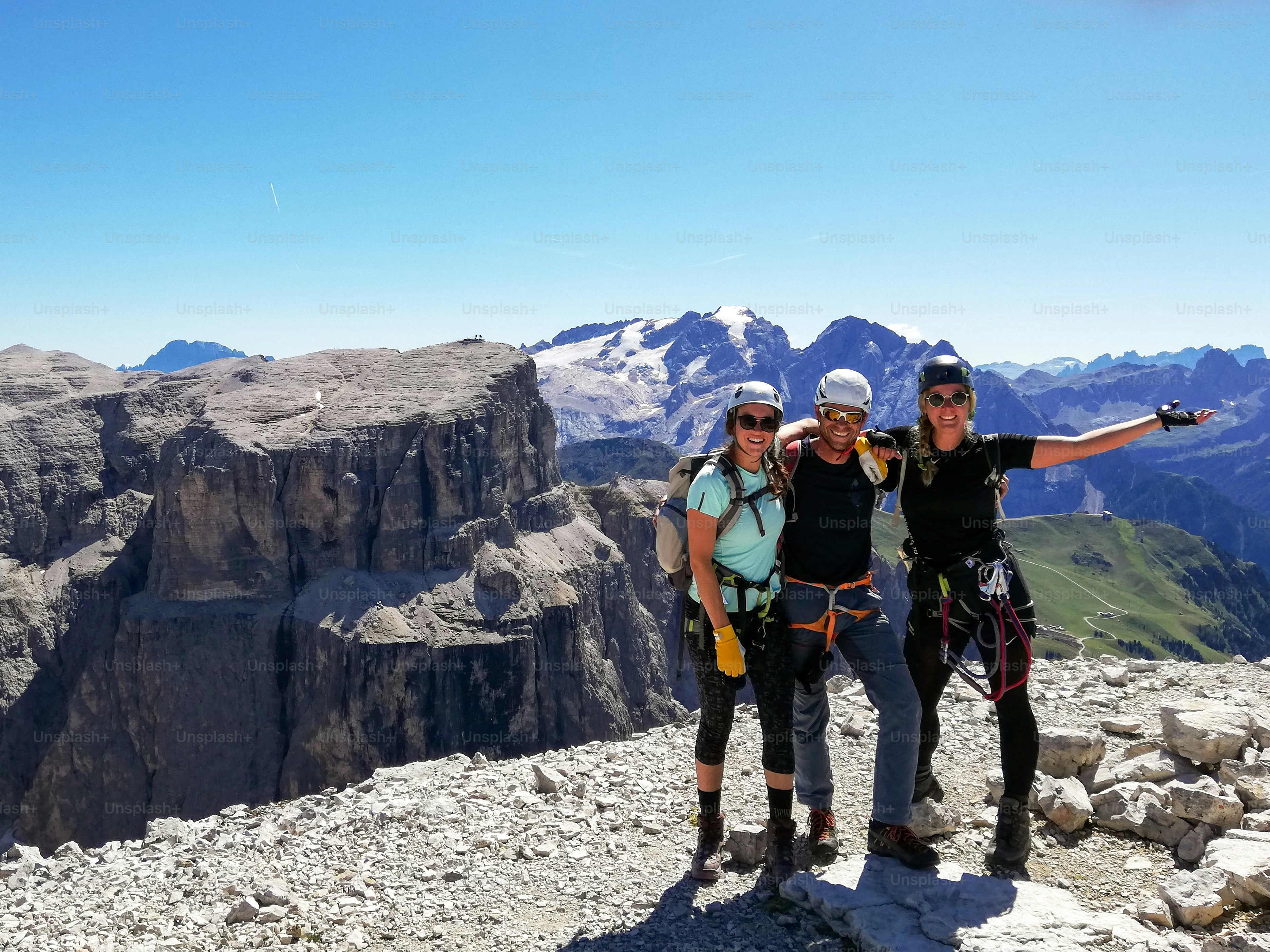 A mountain guide and two female climbers celebrate standing on the ...