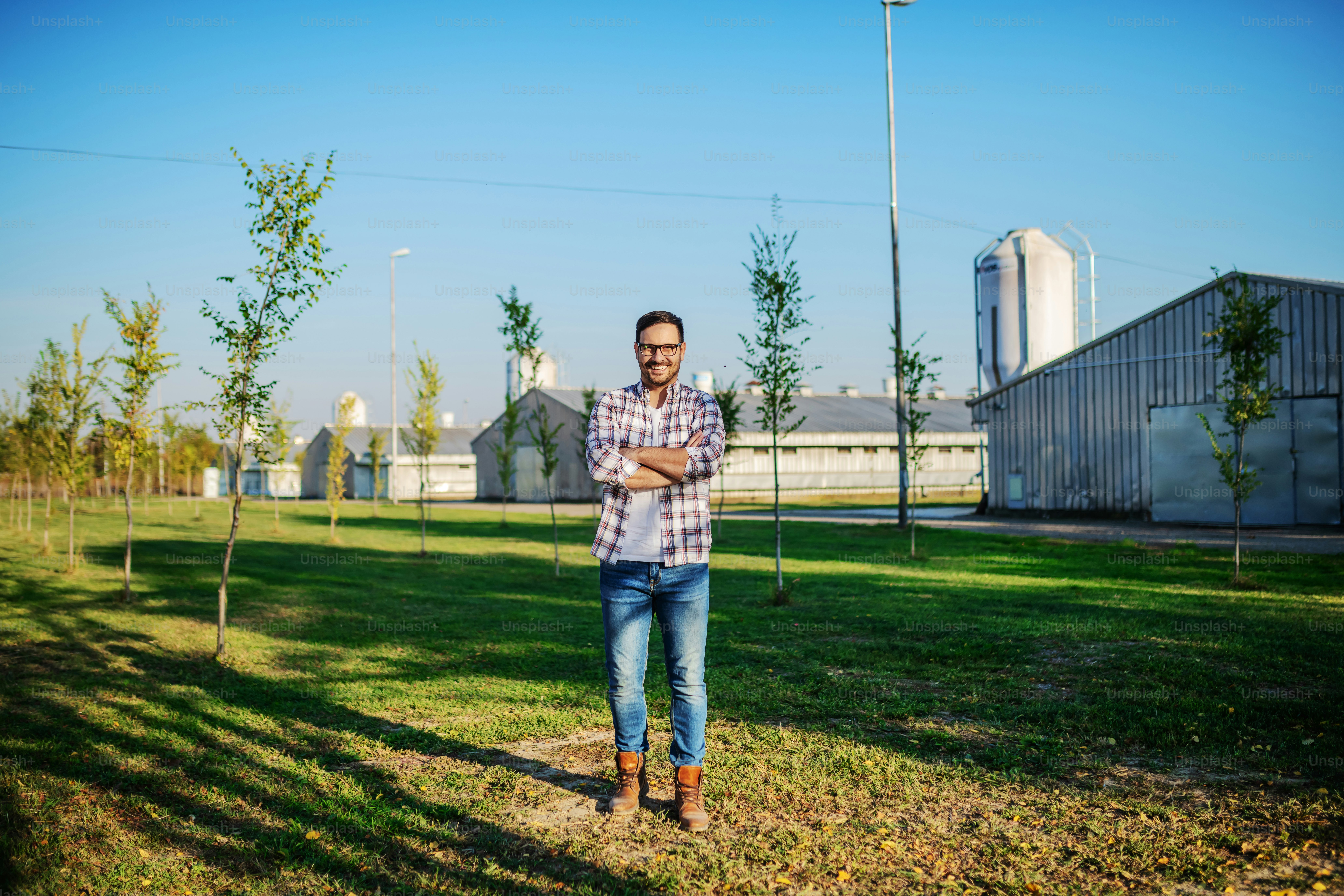 Handsome caucasian smiling farmer in plaid shirt and jeans standing ...
