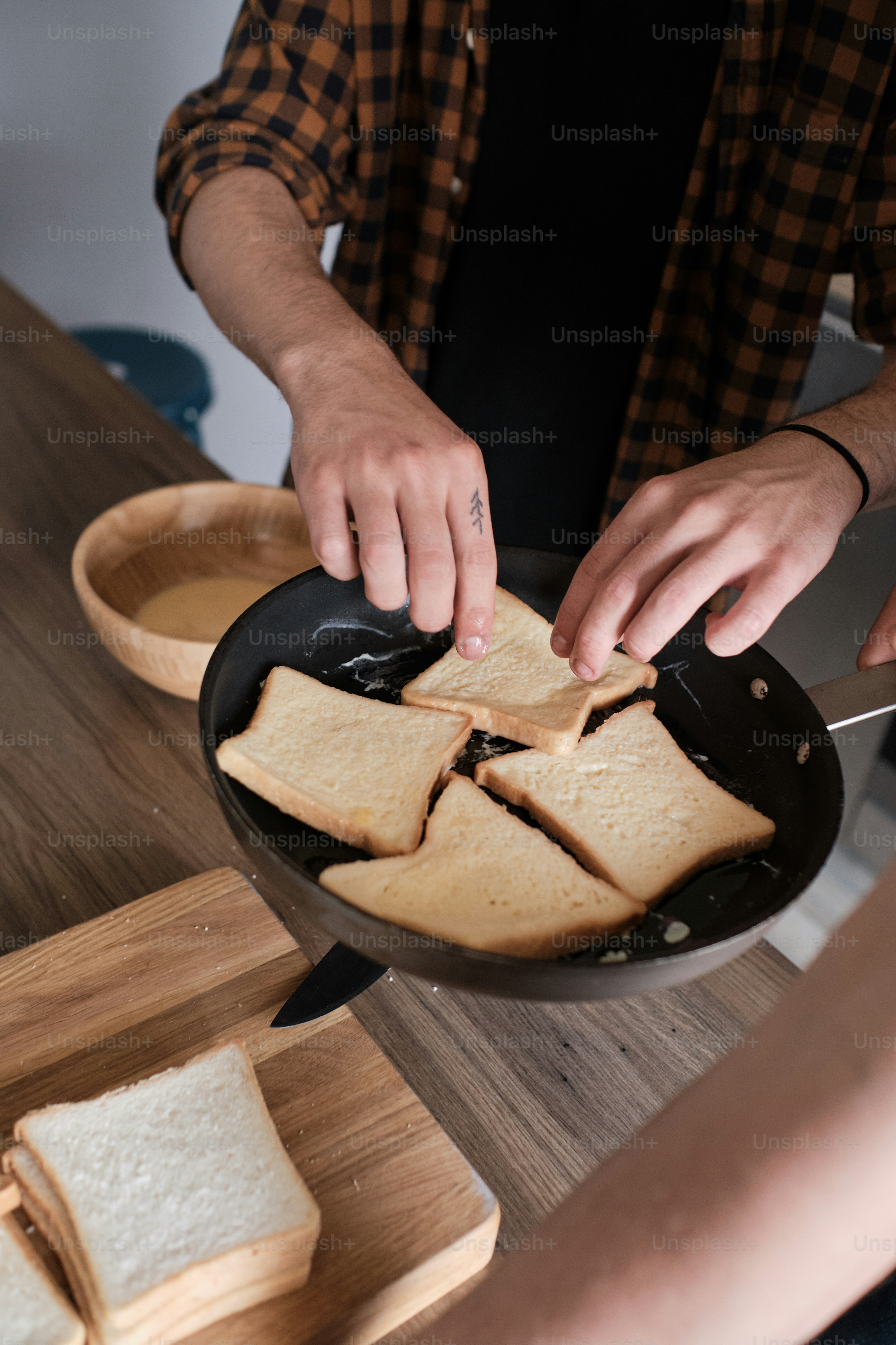 Close up of two mid age bearded men cooking toasts for breakfast in the ...