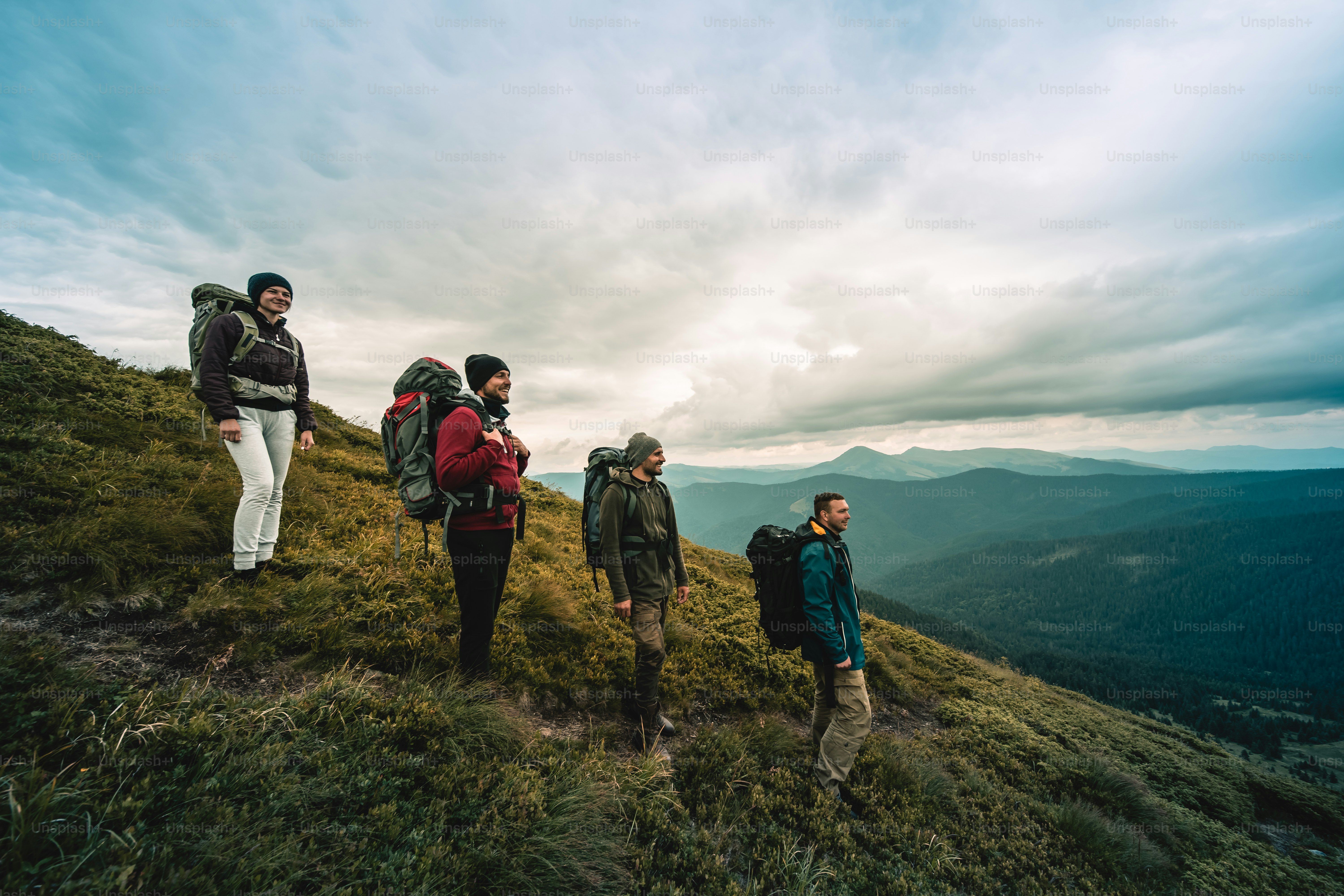 The four hikers with backpacks standing on the mountain photo – Sports ...