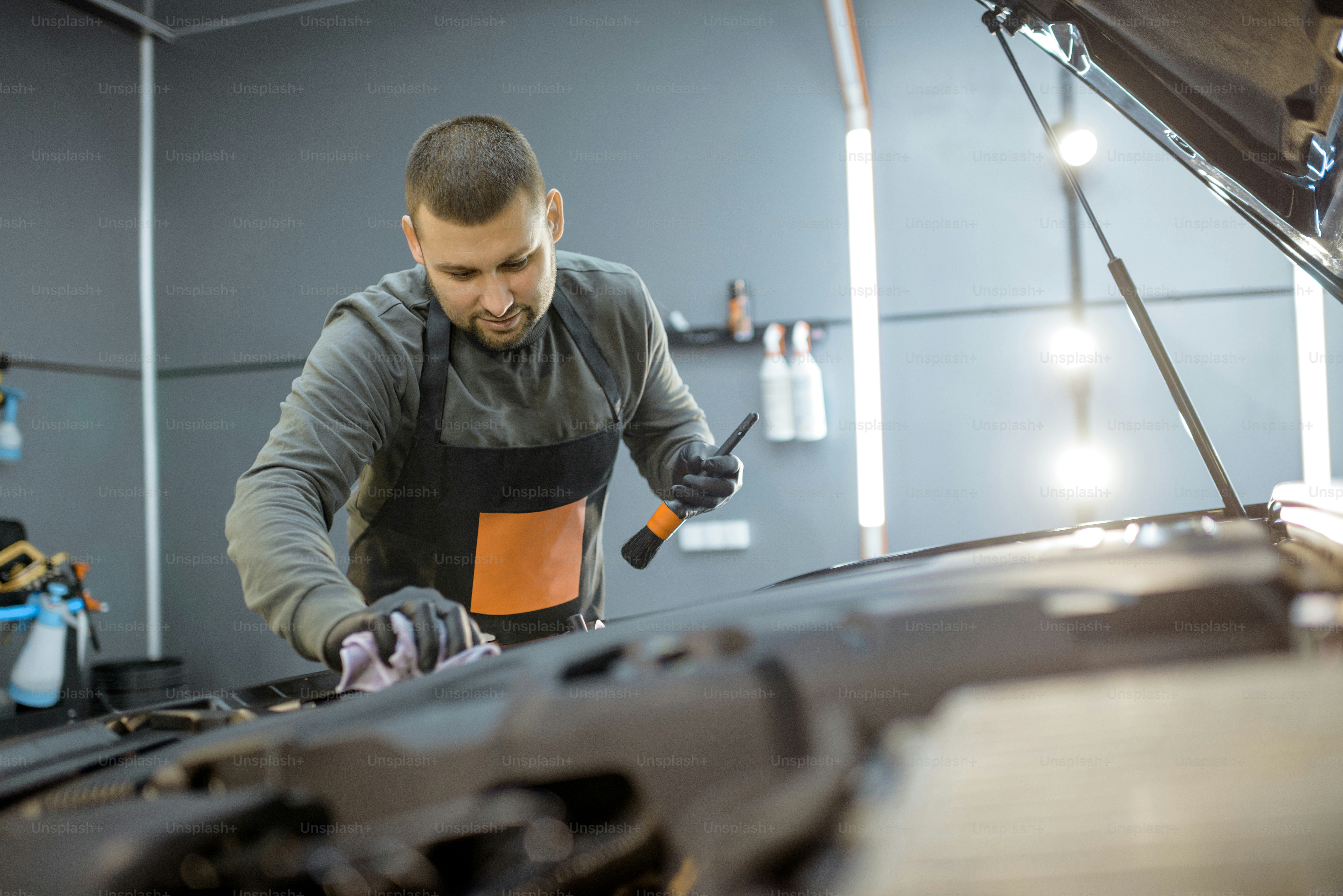 Service worker in uniform performs a professional car cleaning, wiping ...