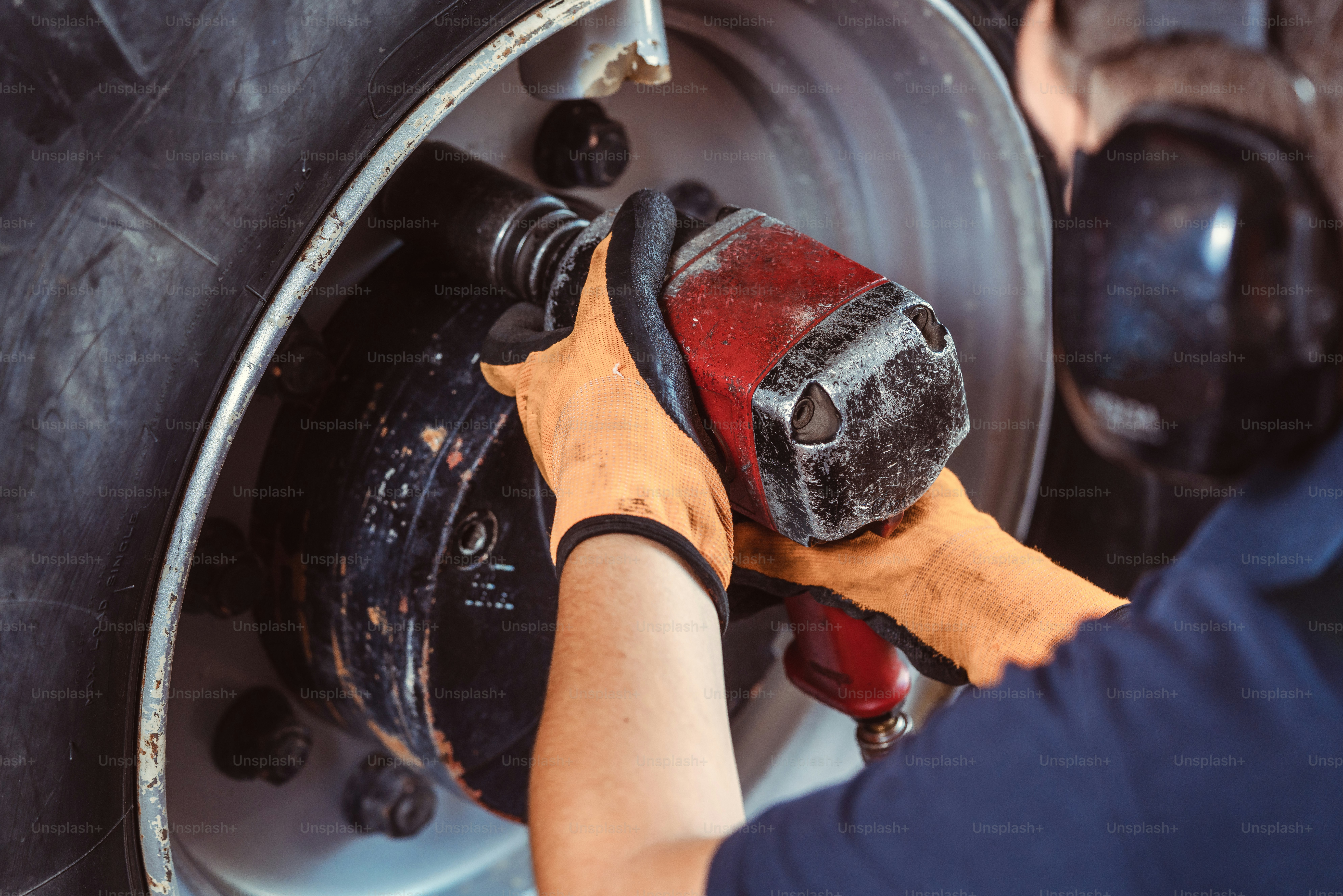 Close-up of farm machine mechanic working on wheel with power tool ...