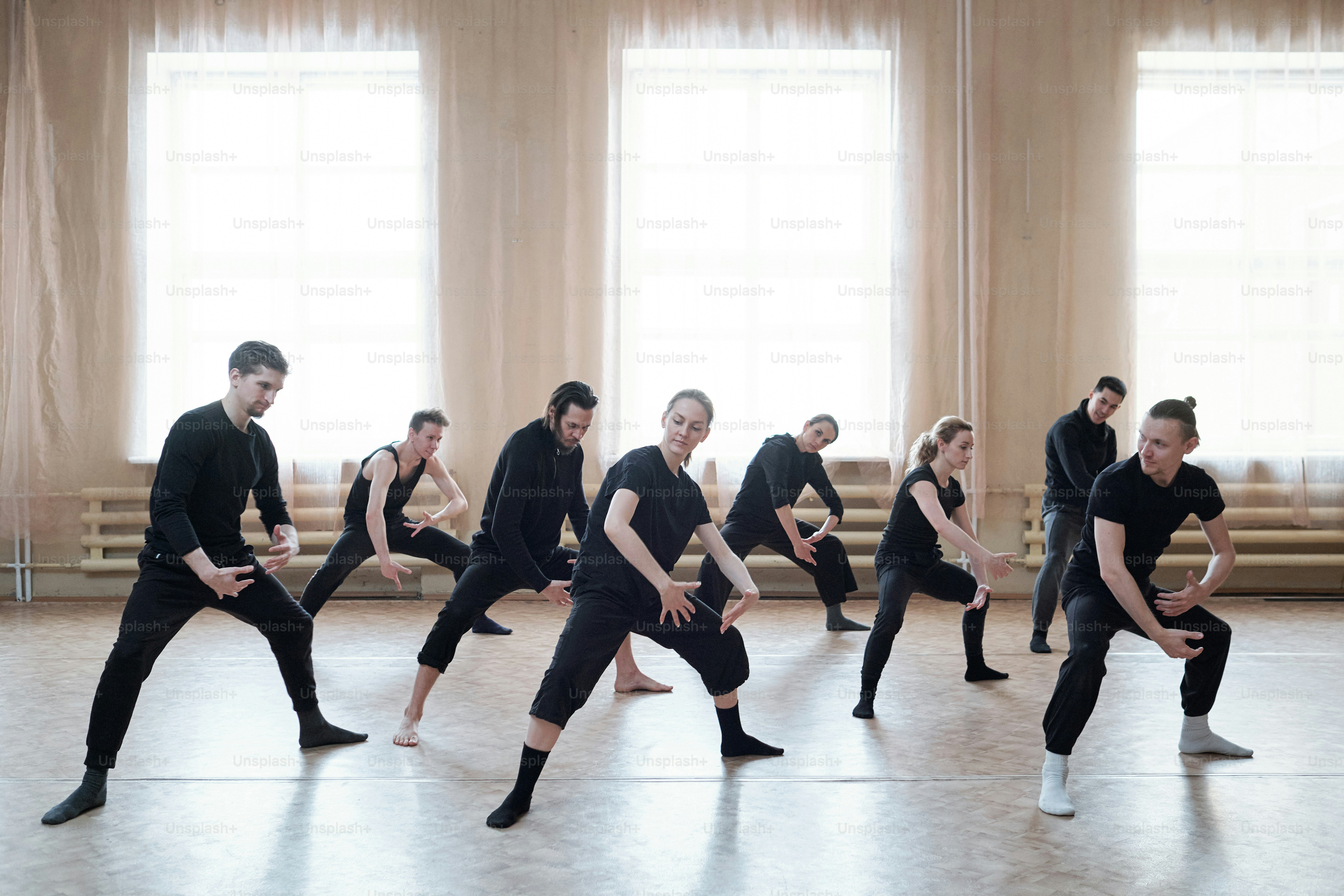 Horizontal shot of young men and women wearing black outfits dancing ...