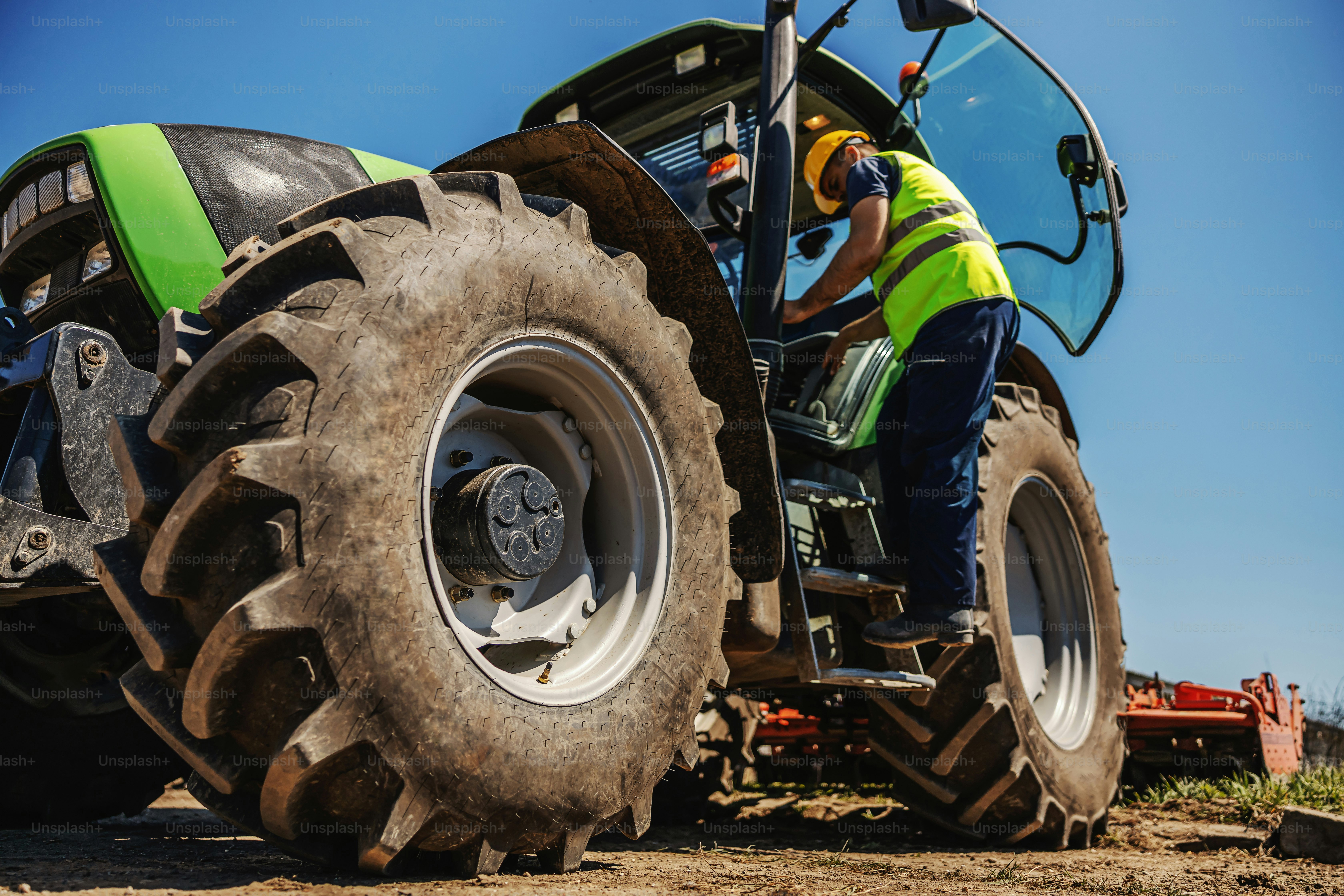 Worker climbing on tractor. photo – Farm tractor Image on Unsplash