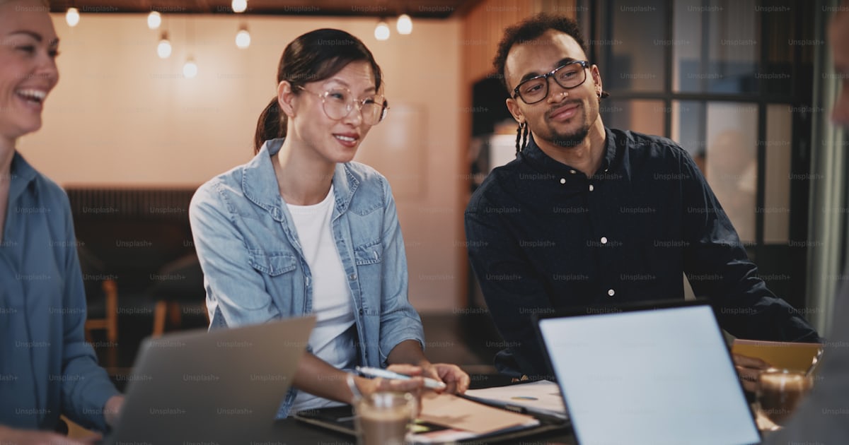 Diverse group of smiling young businesspeople talking together during a ... Diverse group of smiling young businesspeople talking together during a ...