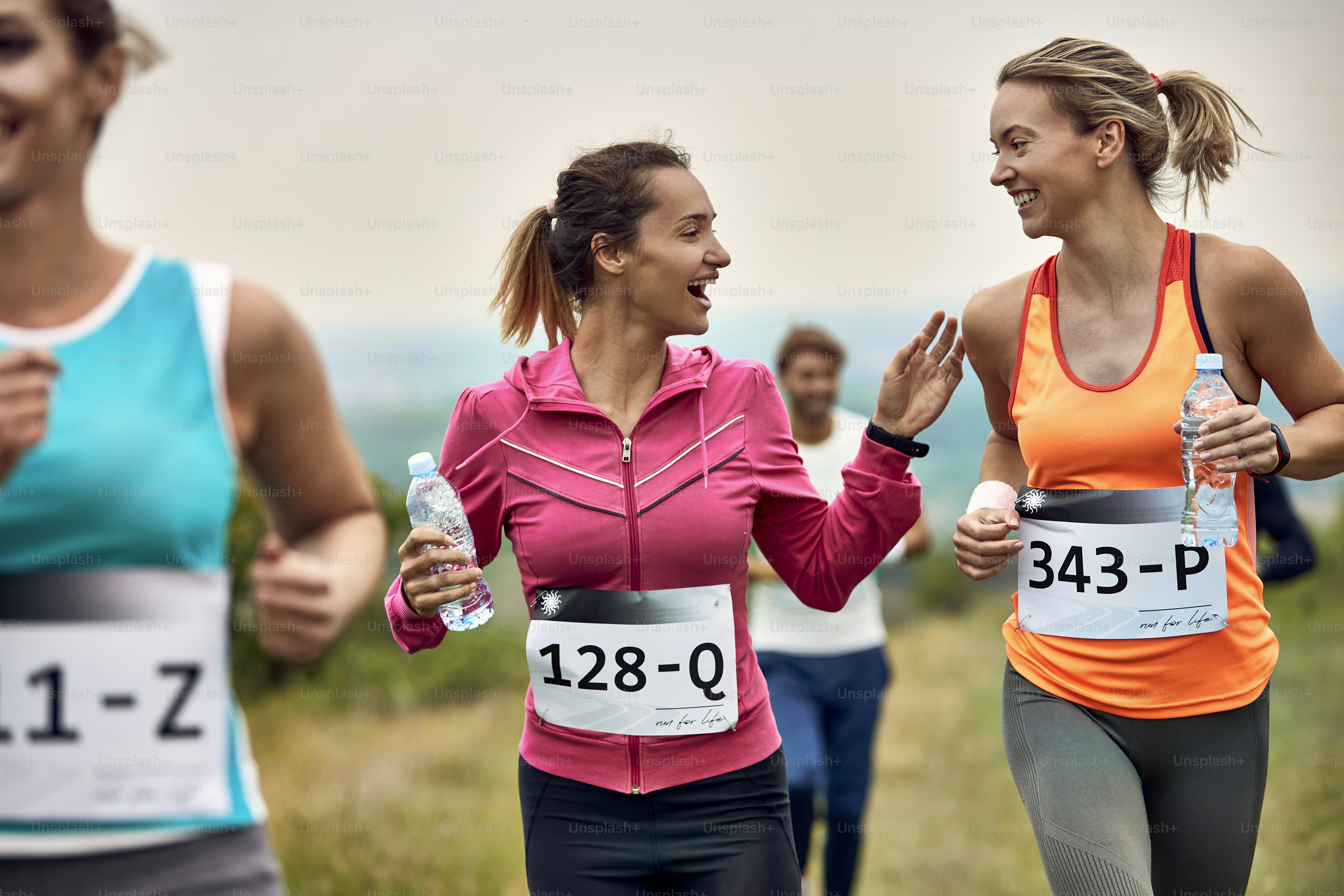 Young happy athletic women talking while running a marathon in nature ...