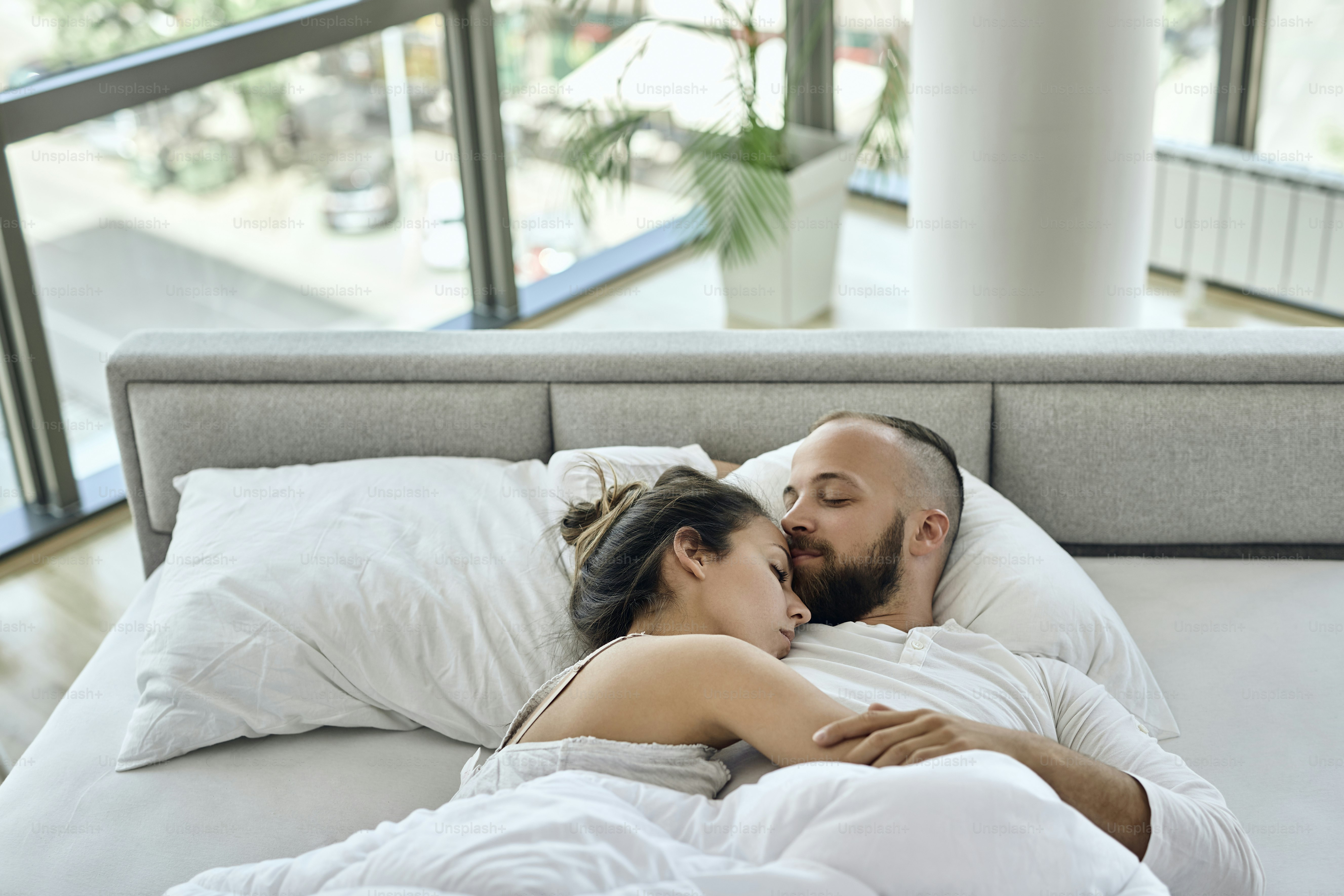 Young loving couple embracing while napping on a bed. photo – Indoors ...