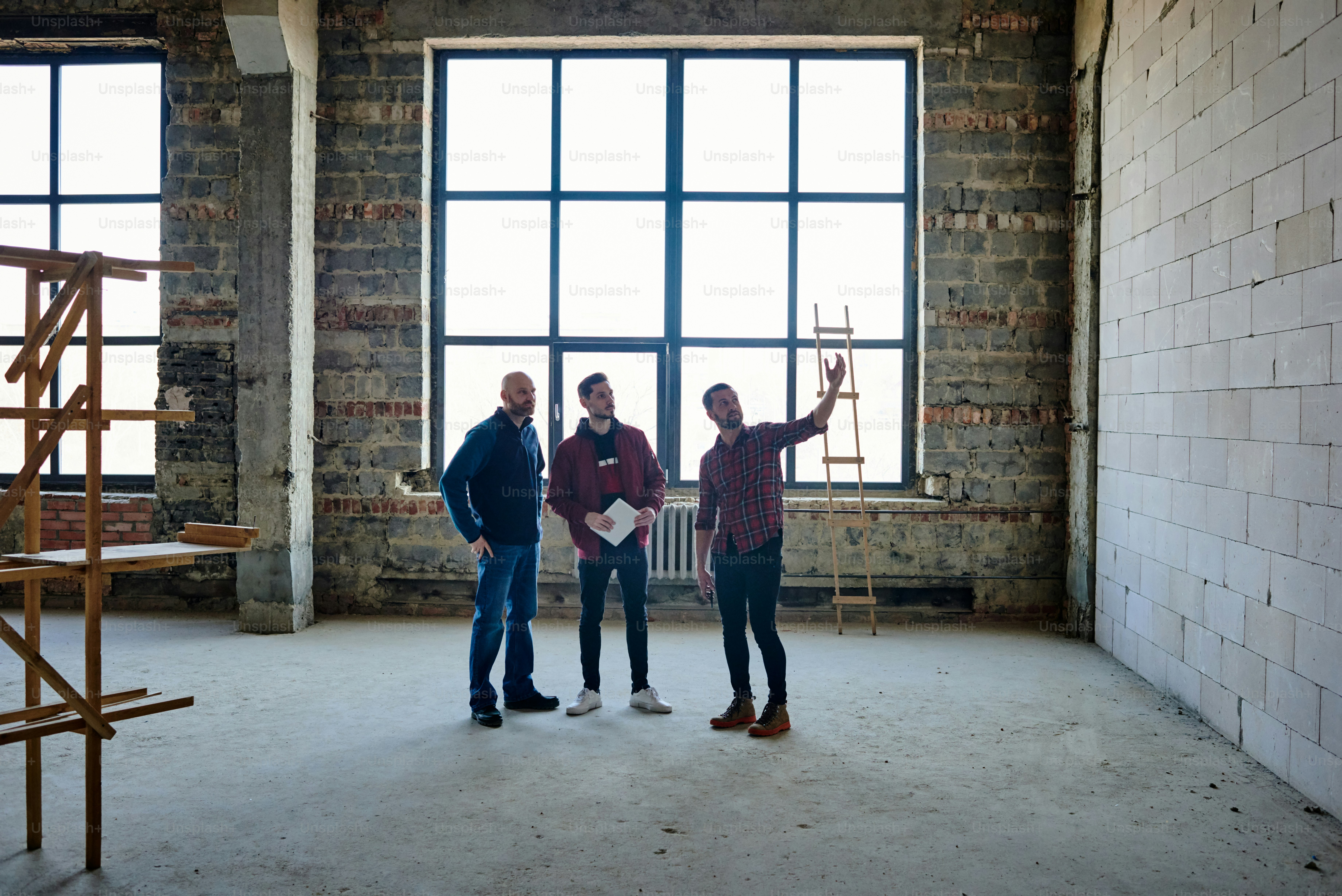Young foreman or contractor pointing at brick wall of unfinished ...
