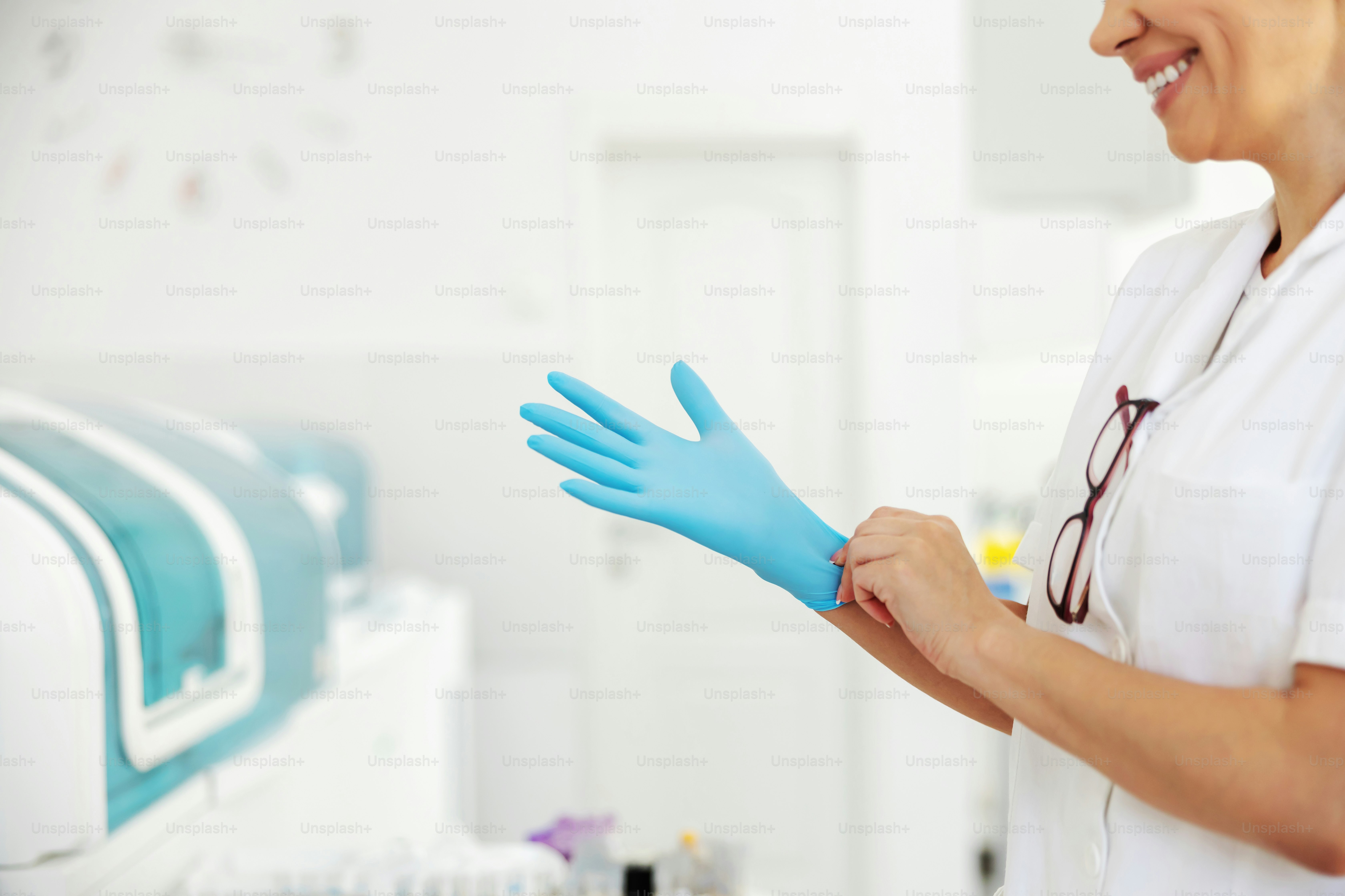 Closeup of smiling attractive female lab assistant in coat putting on ...