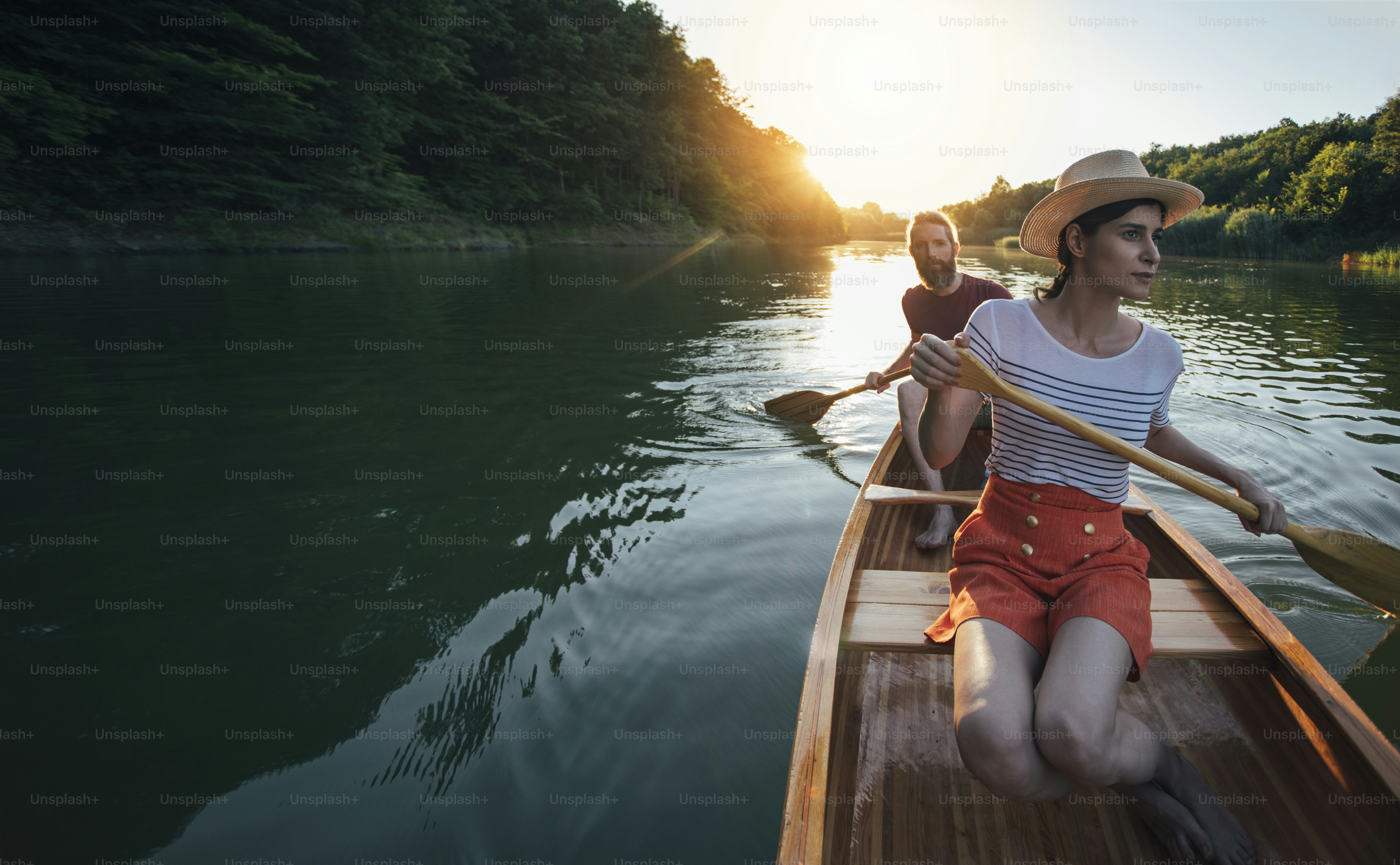 Couple enjoy paddling canoe on the sunset lake. Woman and man on a ...