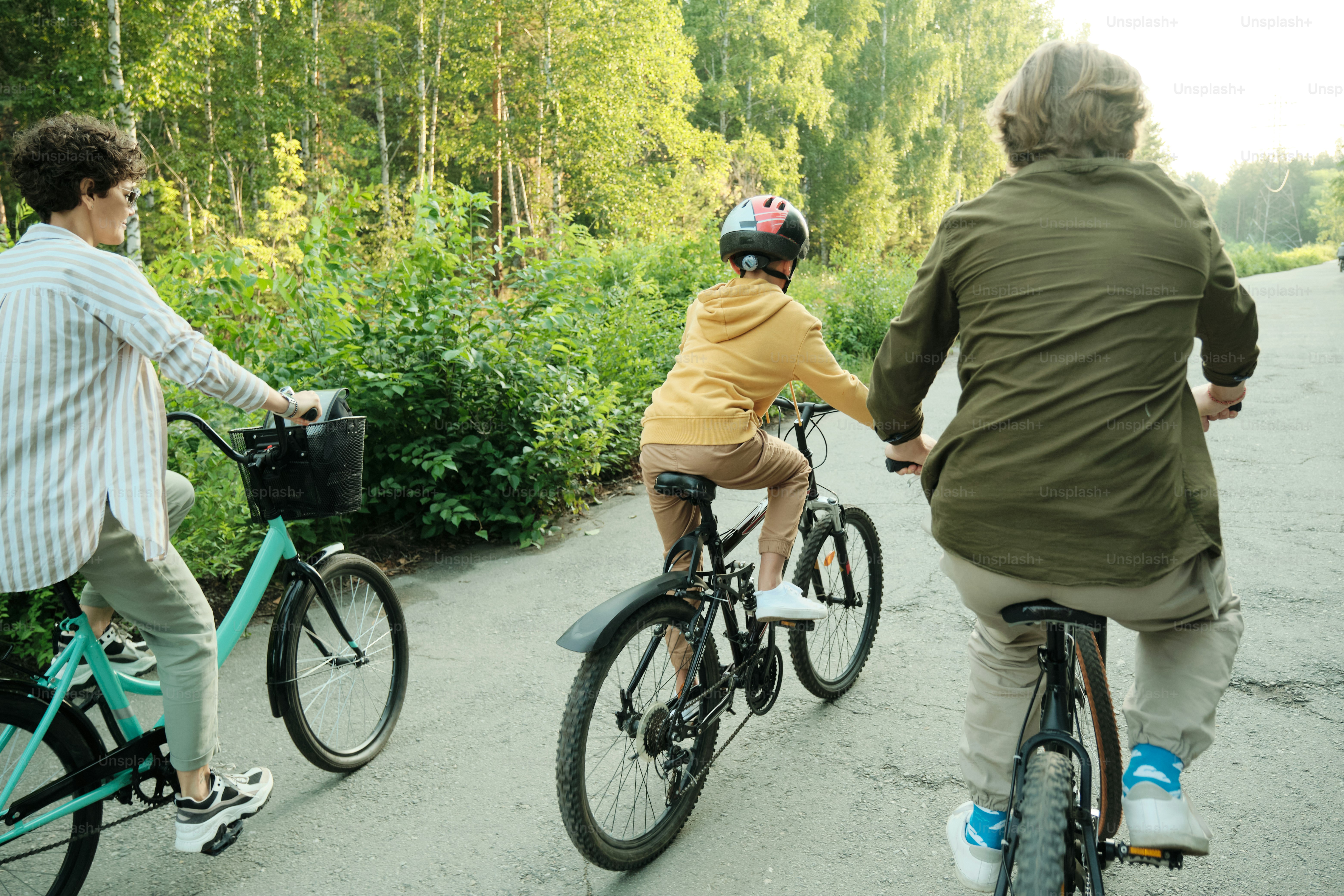 Happy active family of young husband, wife and son riding bicycles ...