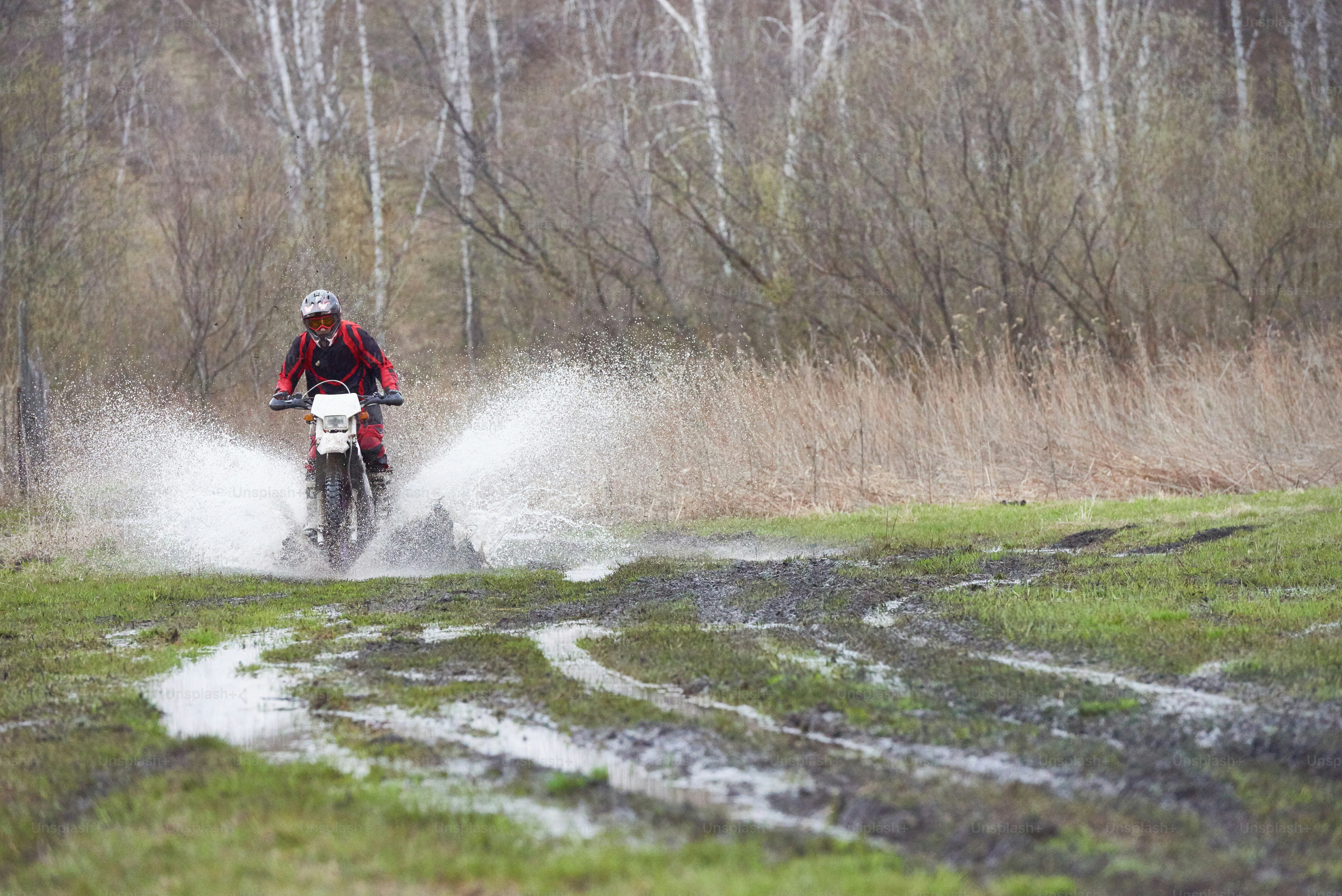 Motorcross rider racing in mud track while moving down country road ...
