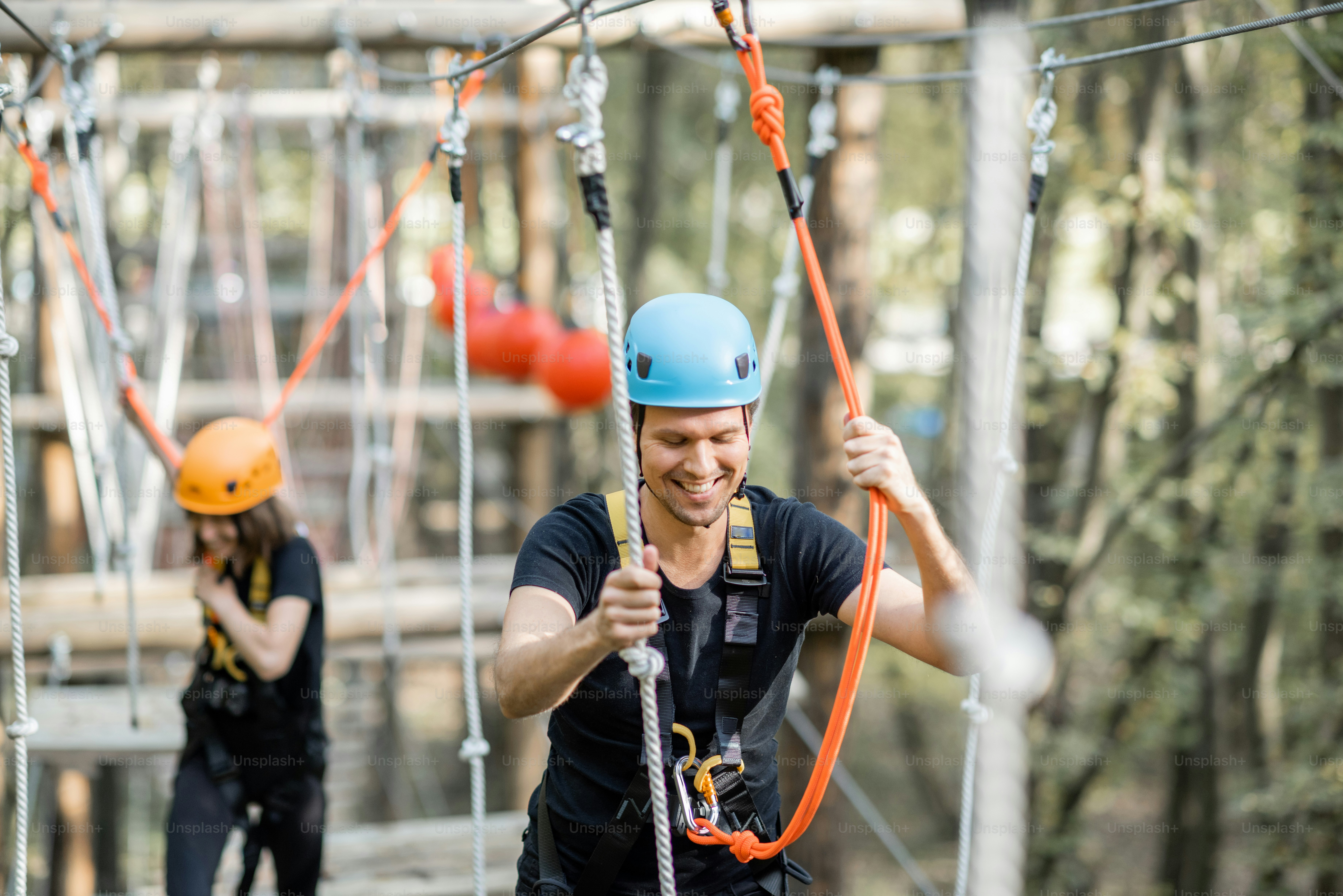 Well-equipped man and woman having an active recreation, climbing ropes ...