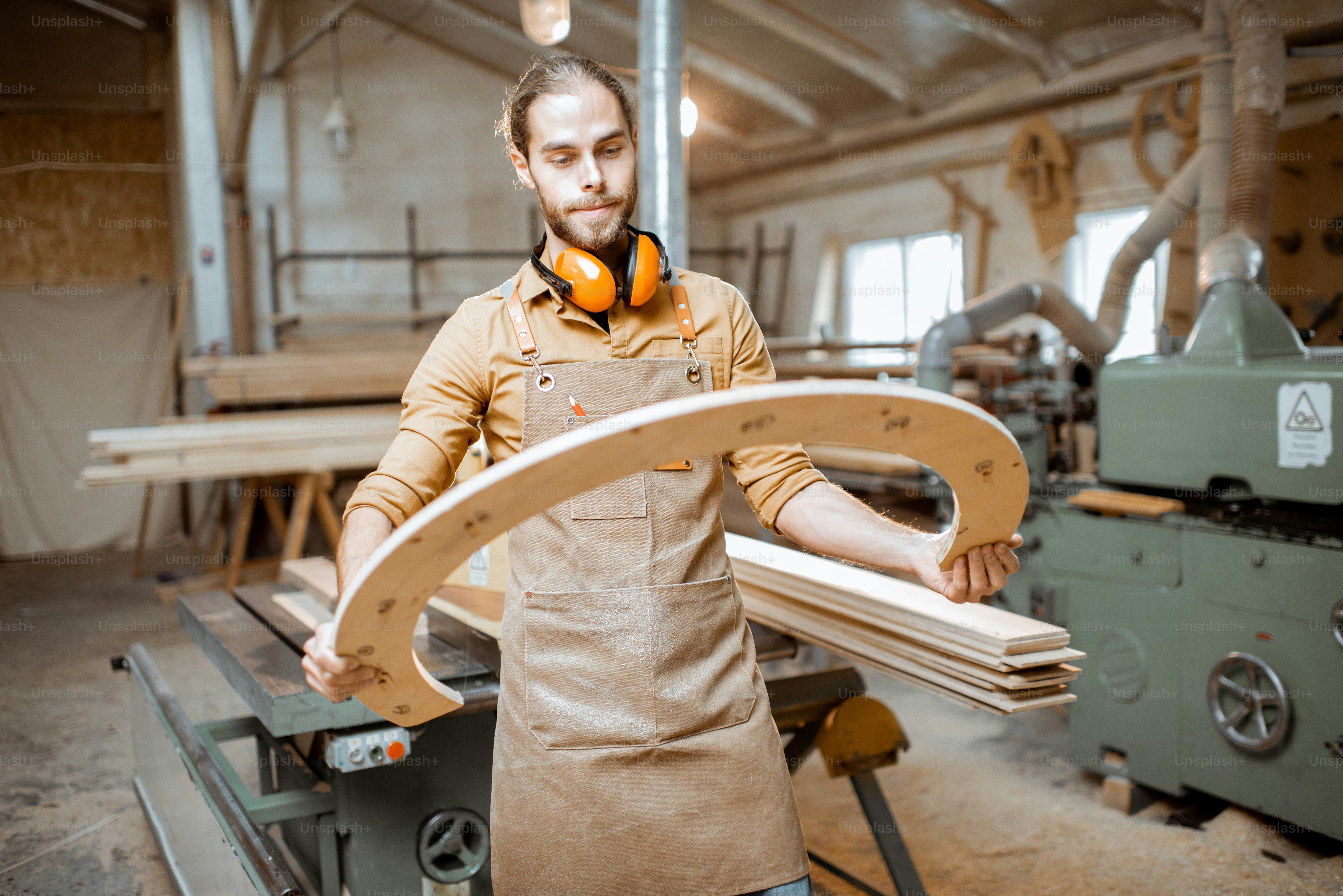 Portrait of a handsome carpenter looking on the wooden product ...