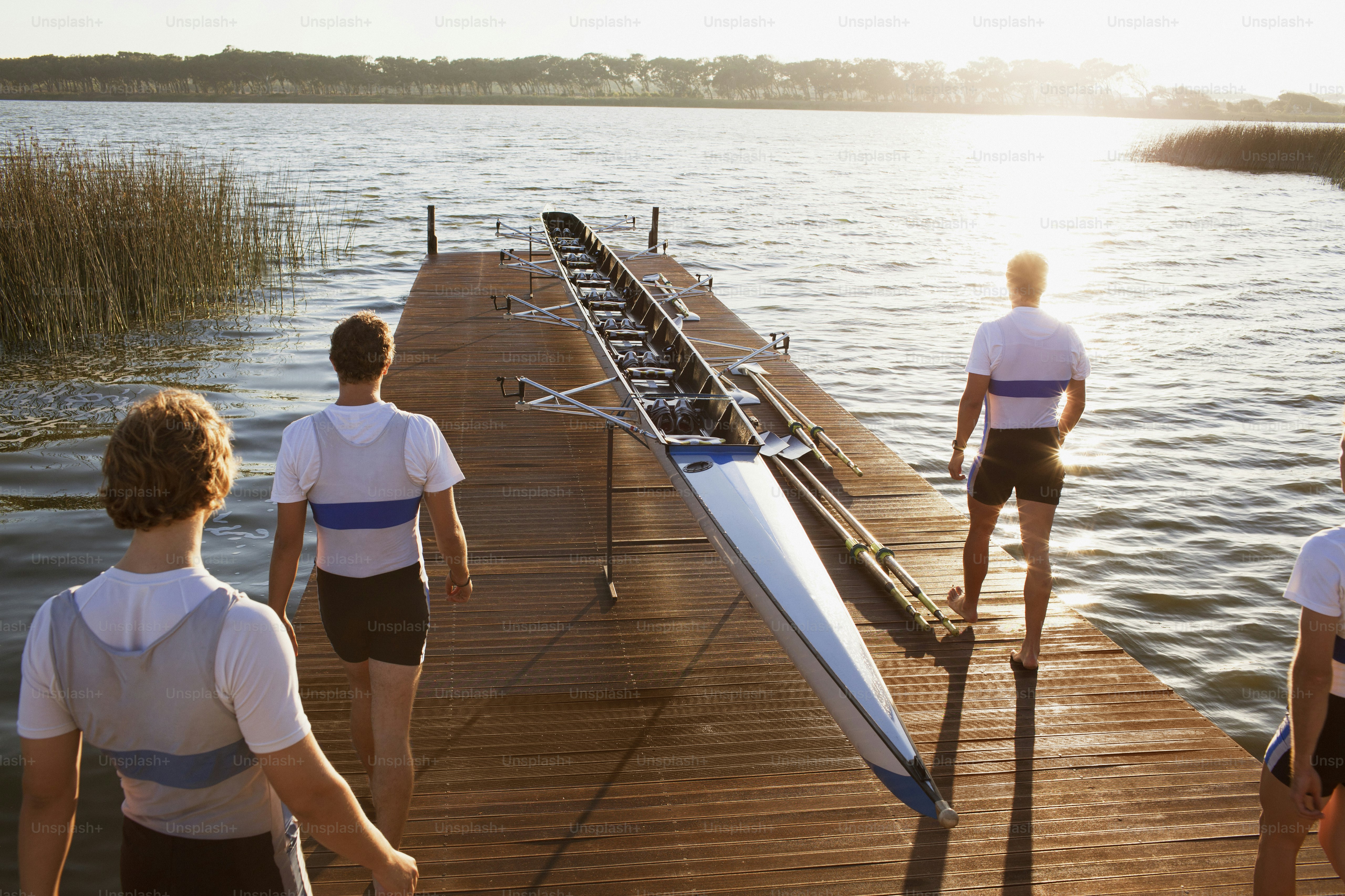 A group of people rowing a long boat in the water photo – Teamwork ...