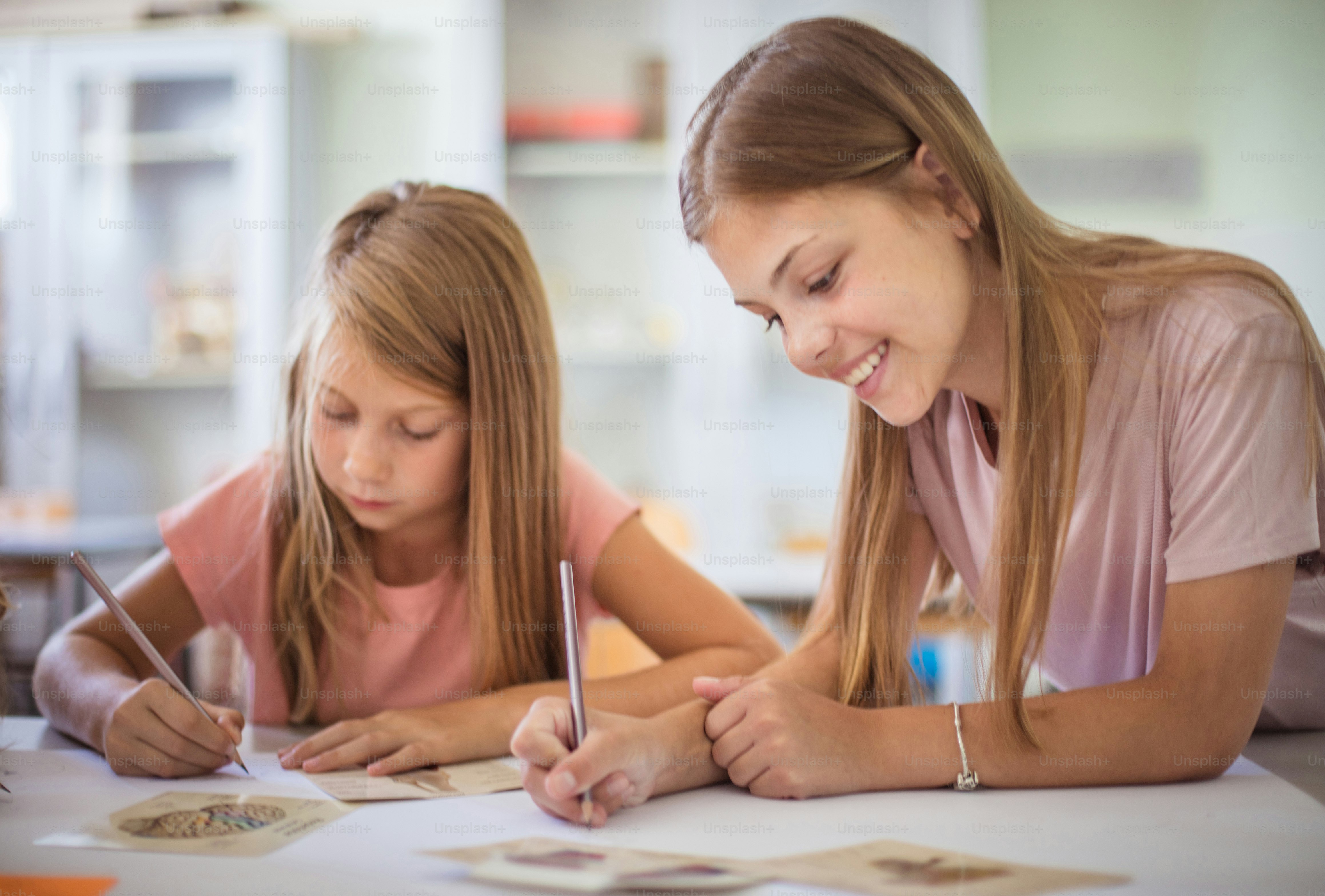 Exam in classroom. Two school girls writing during class. Close up ...