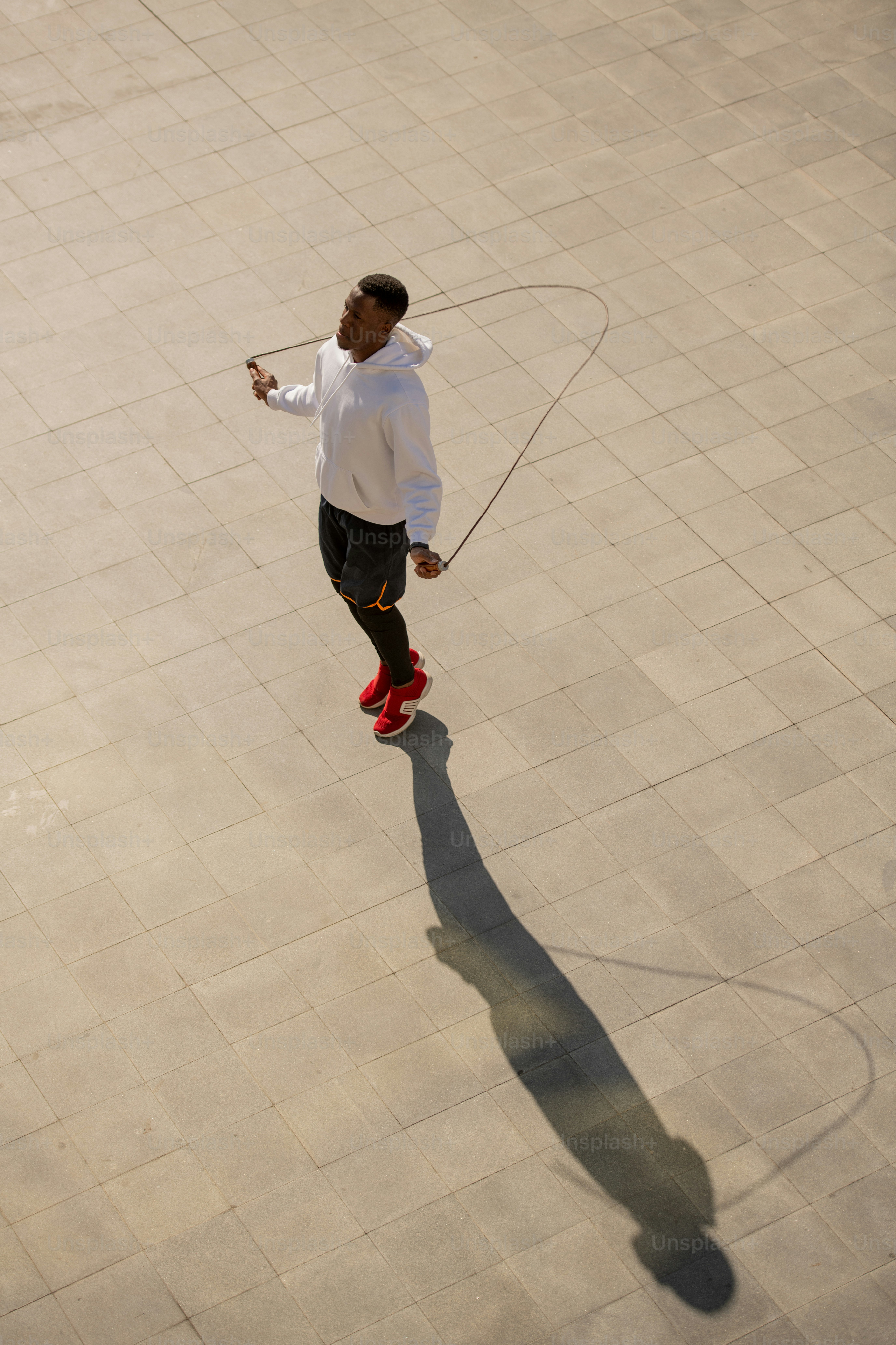Young African sportsman in activewear jumping with skipping-rope in ...