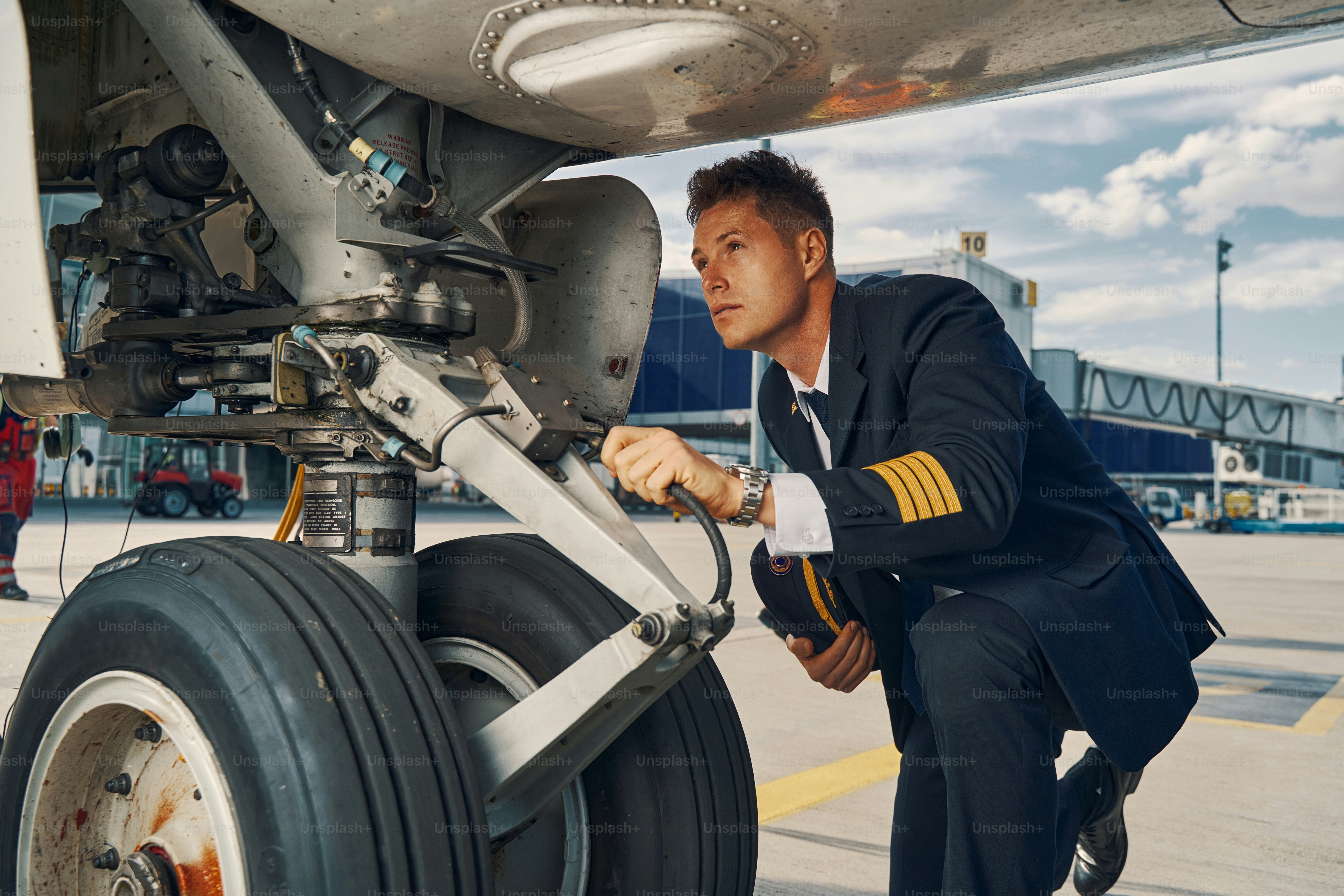 Focused young aviator dressed in uniform carrying out a visual ...