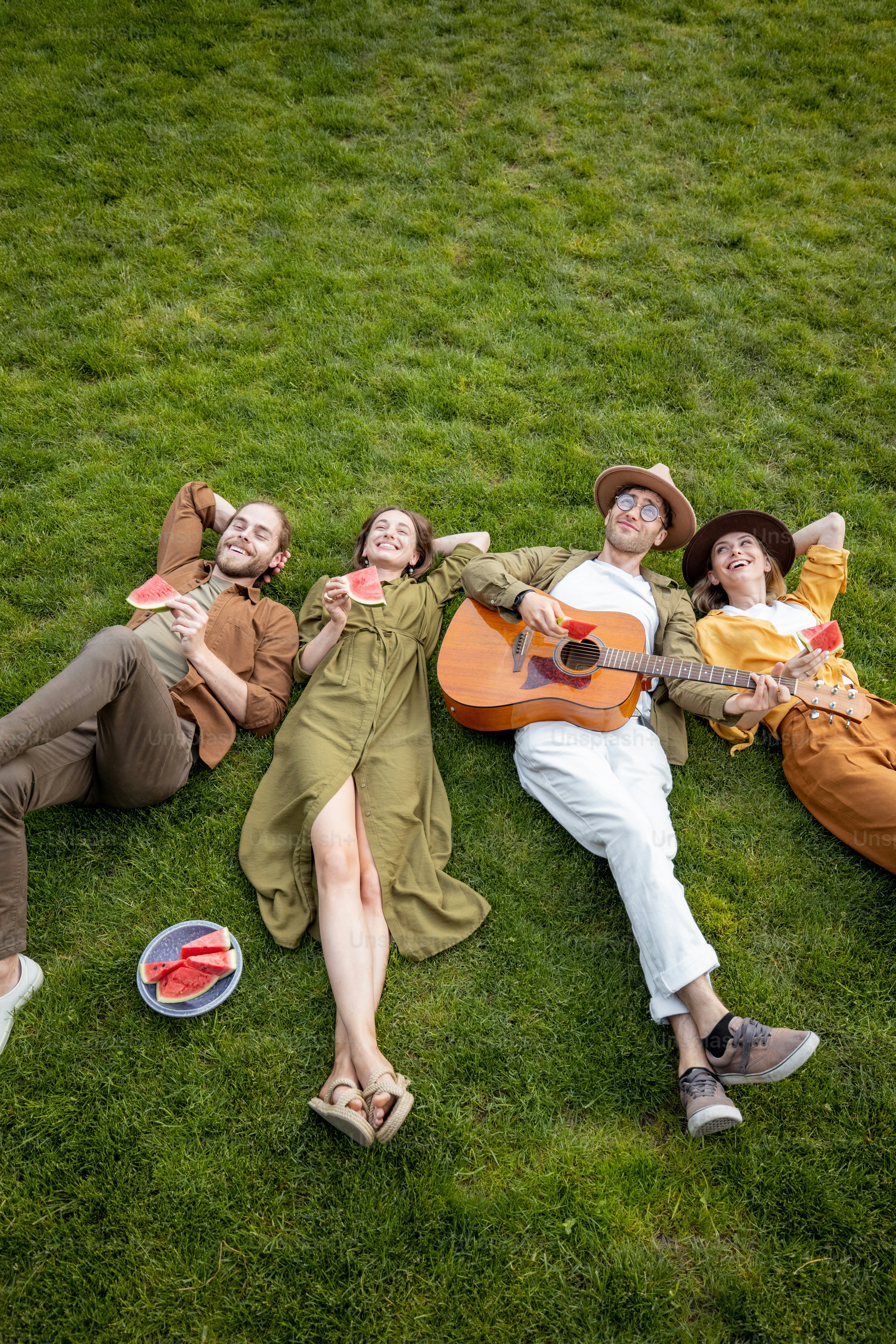 Four young friends spending summer time together lying with watermelons ...