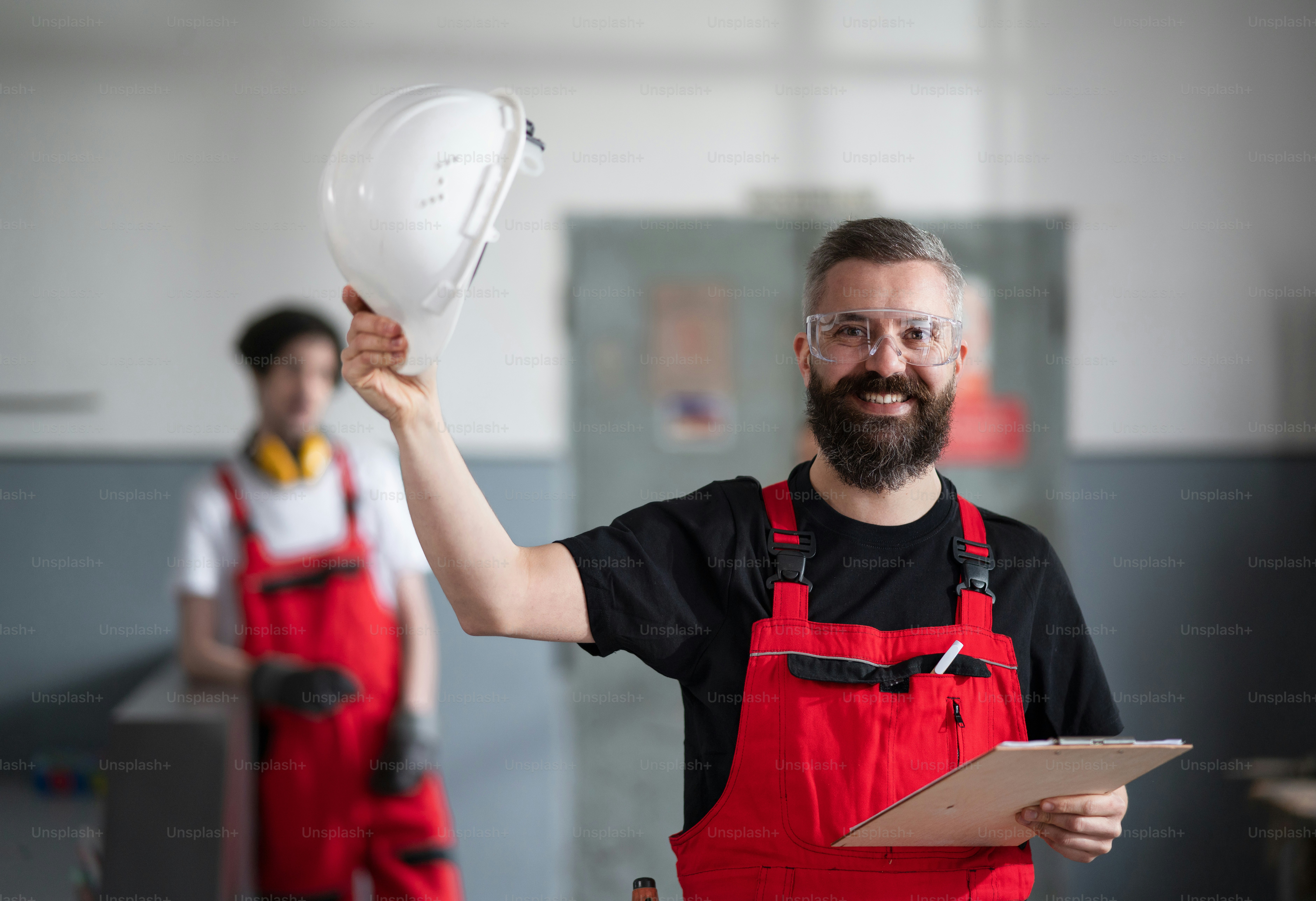 A portrait of cheerful worker with helmet and protective glasses ...