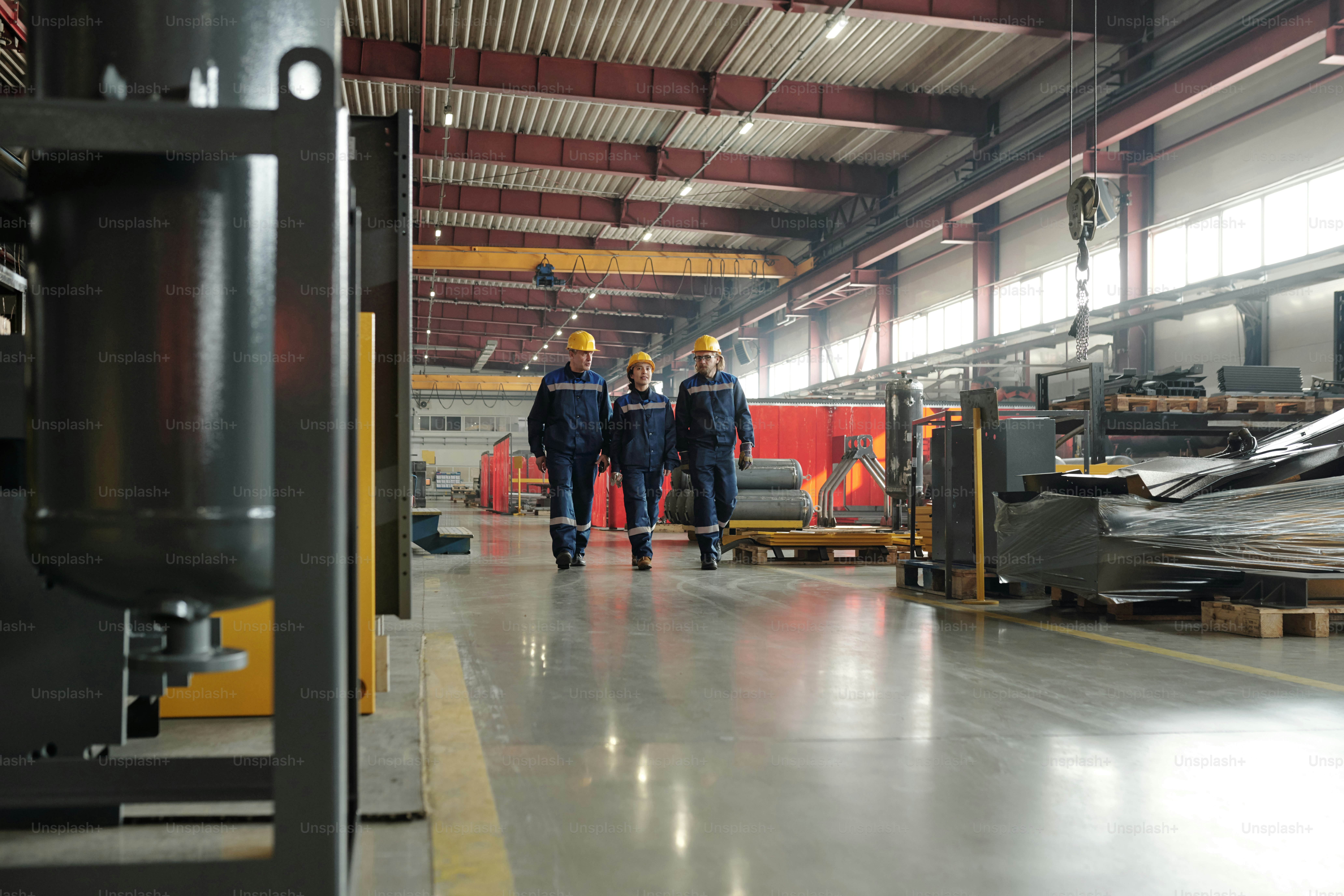 Team of factory workers in hardhats crossing compressor plant workshop ...