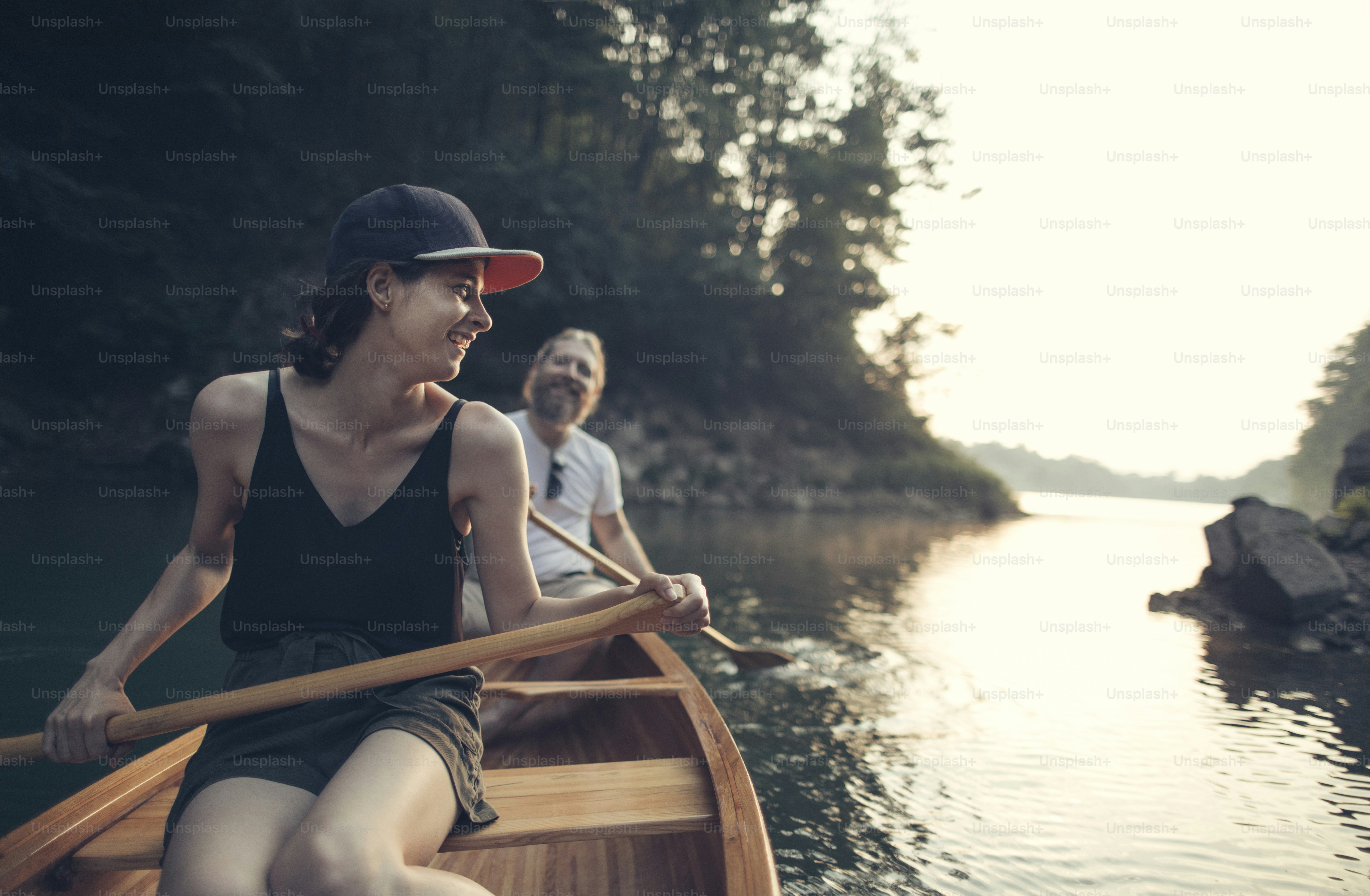 Smiling couple paddling canoe on a lake, copy space. photo – Canoe ...