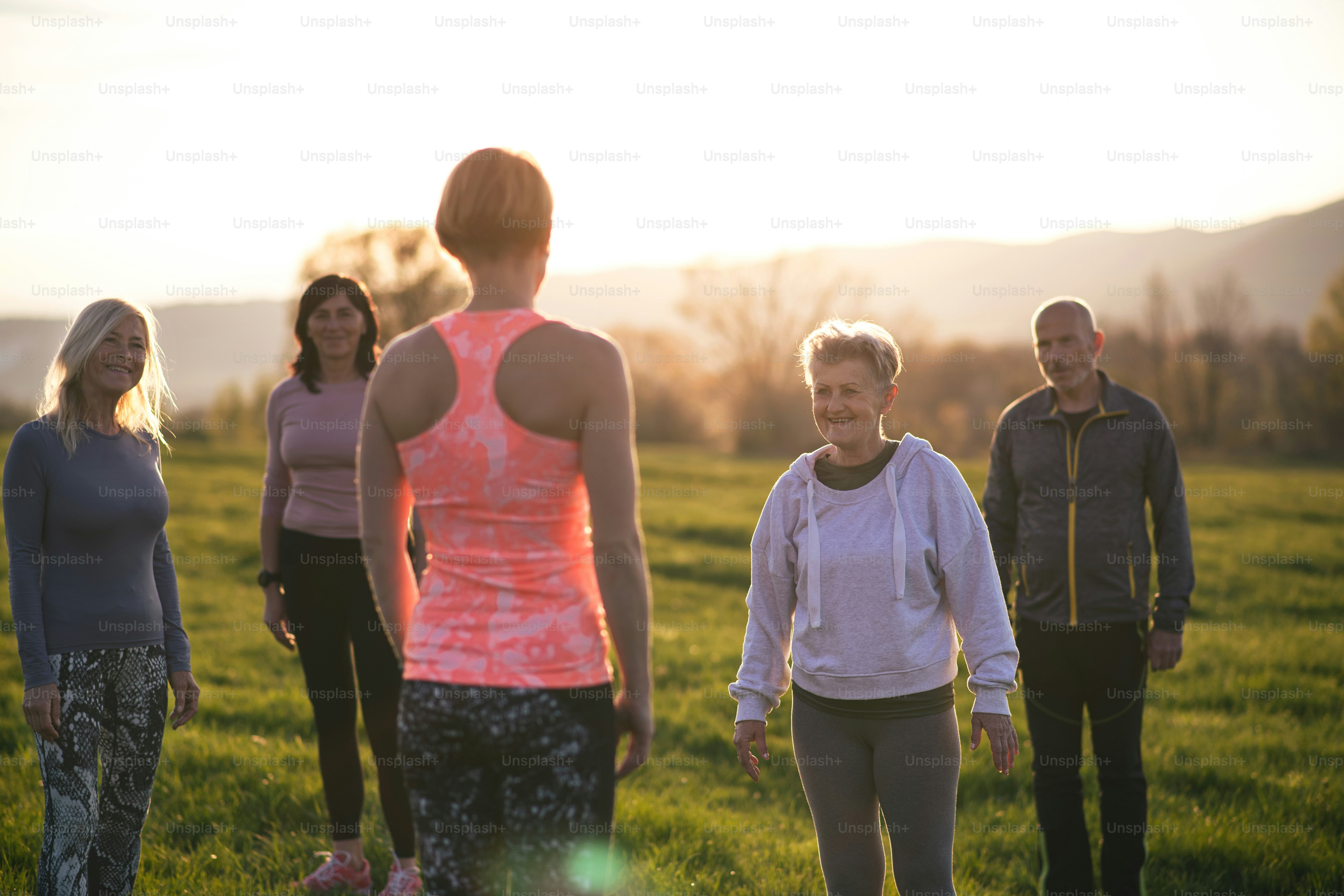 A group of seniors with sport instructor doing exercise outdoors in ...