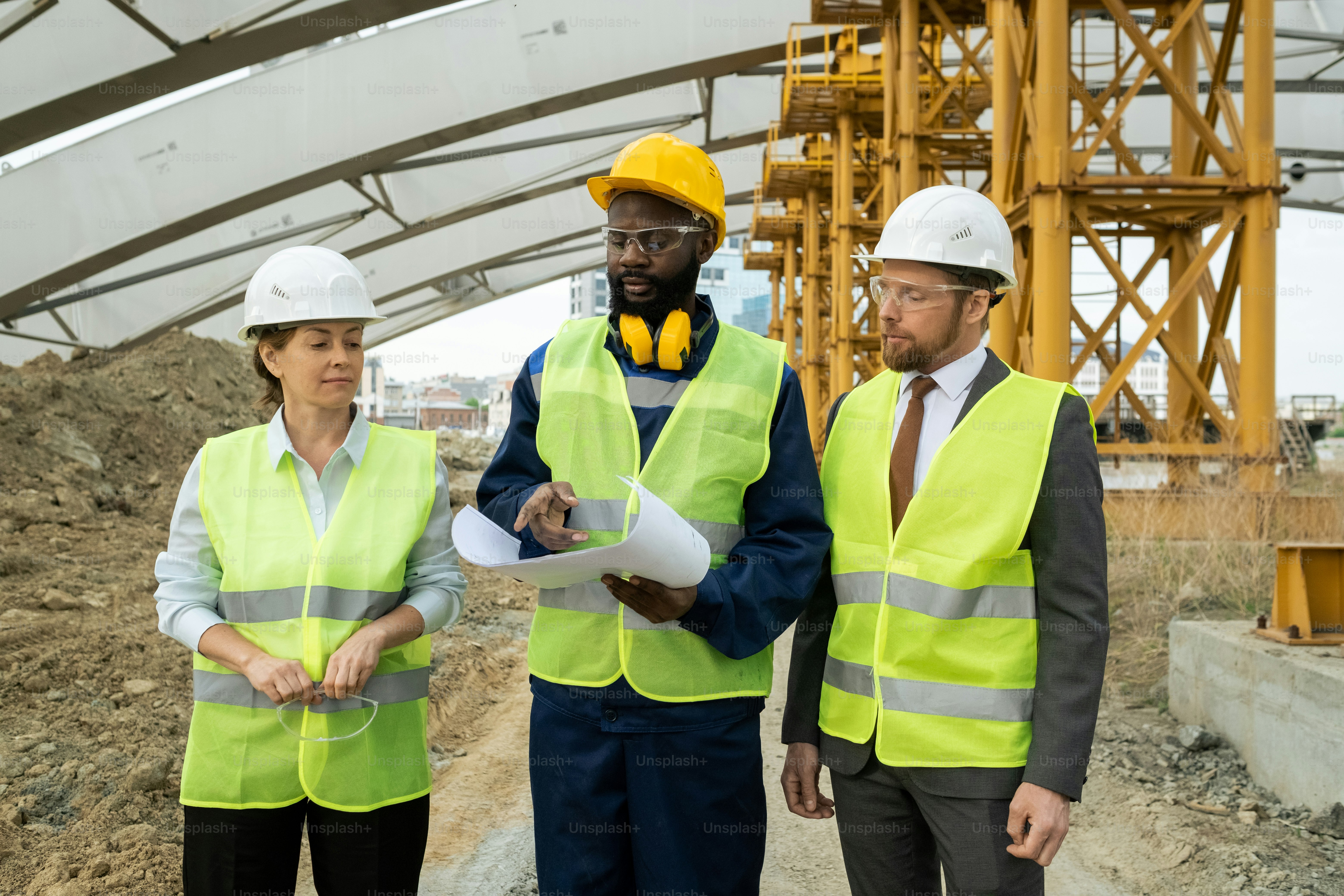 Group of engineers examining blueprint and discussing new construction ...