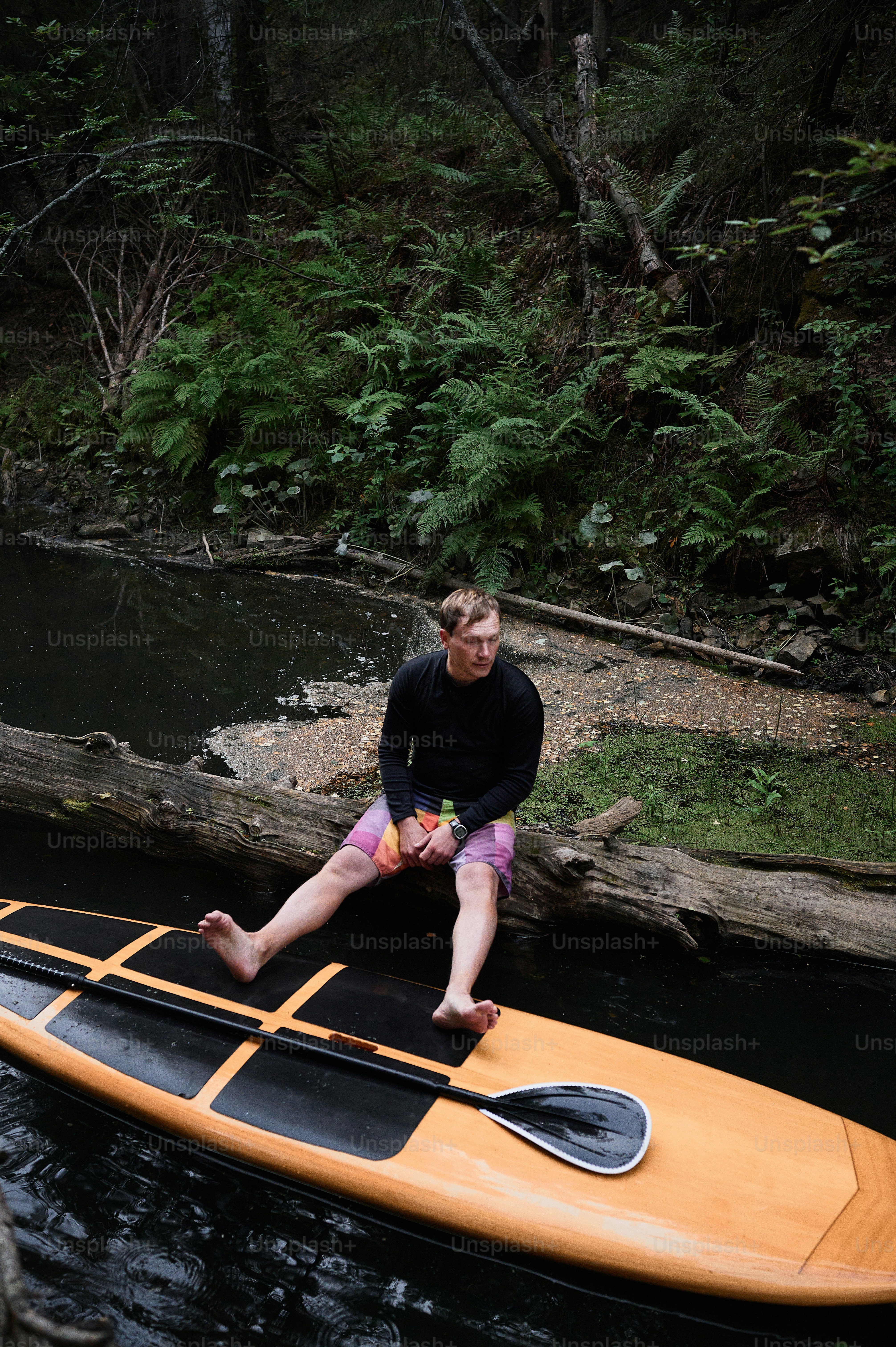 Up above photo of a man taking a break while paddling on the board. He ...