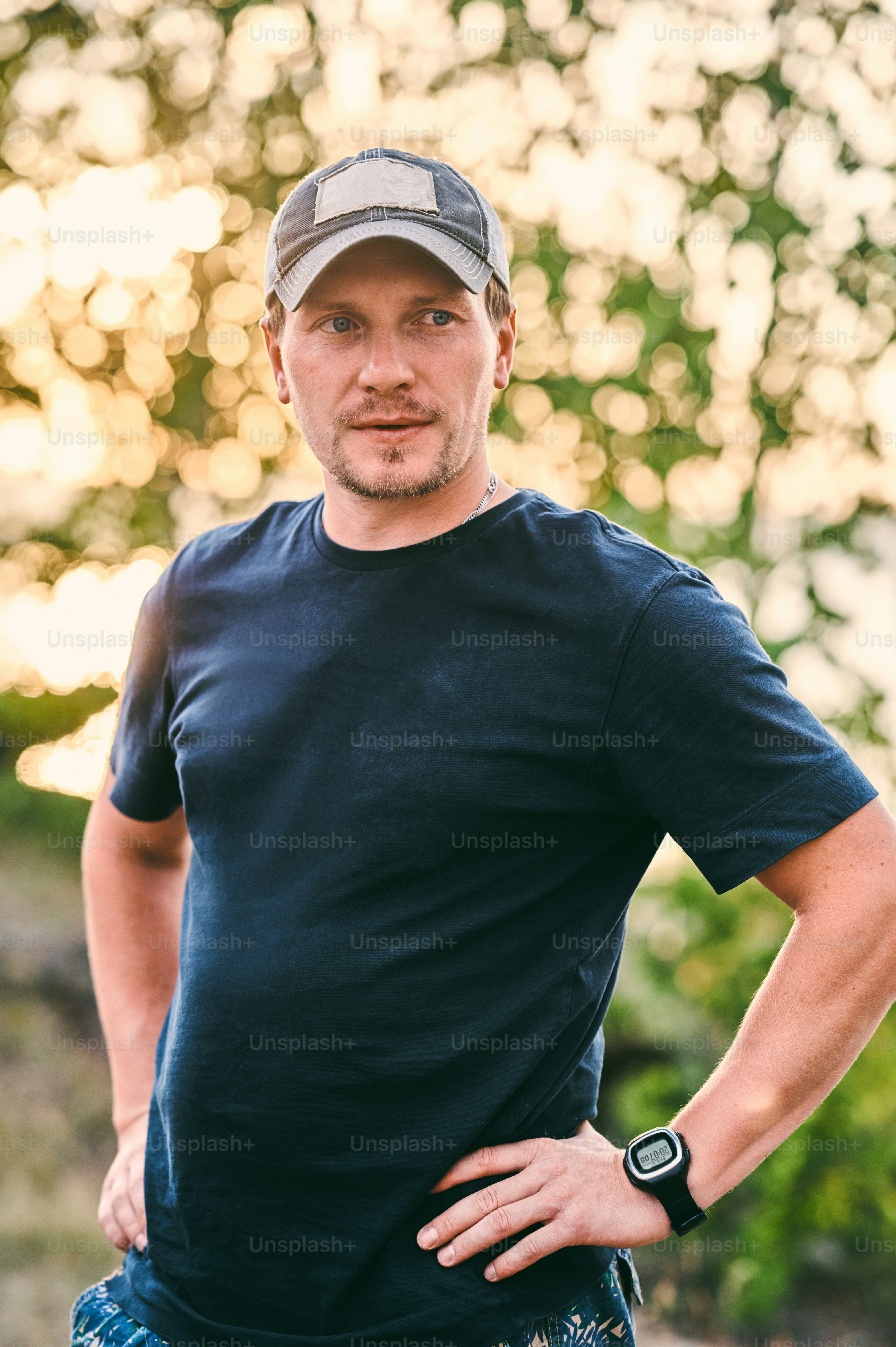 Portrait of strong man wearing a cap and watch, standing outdoors on ...